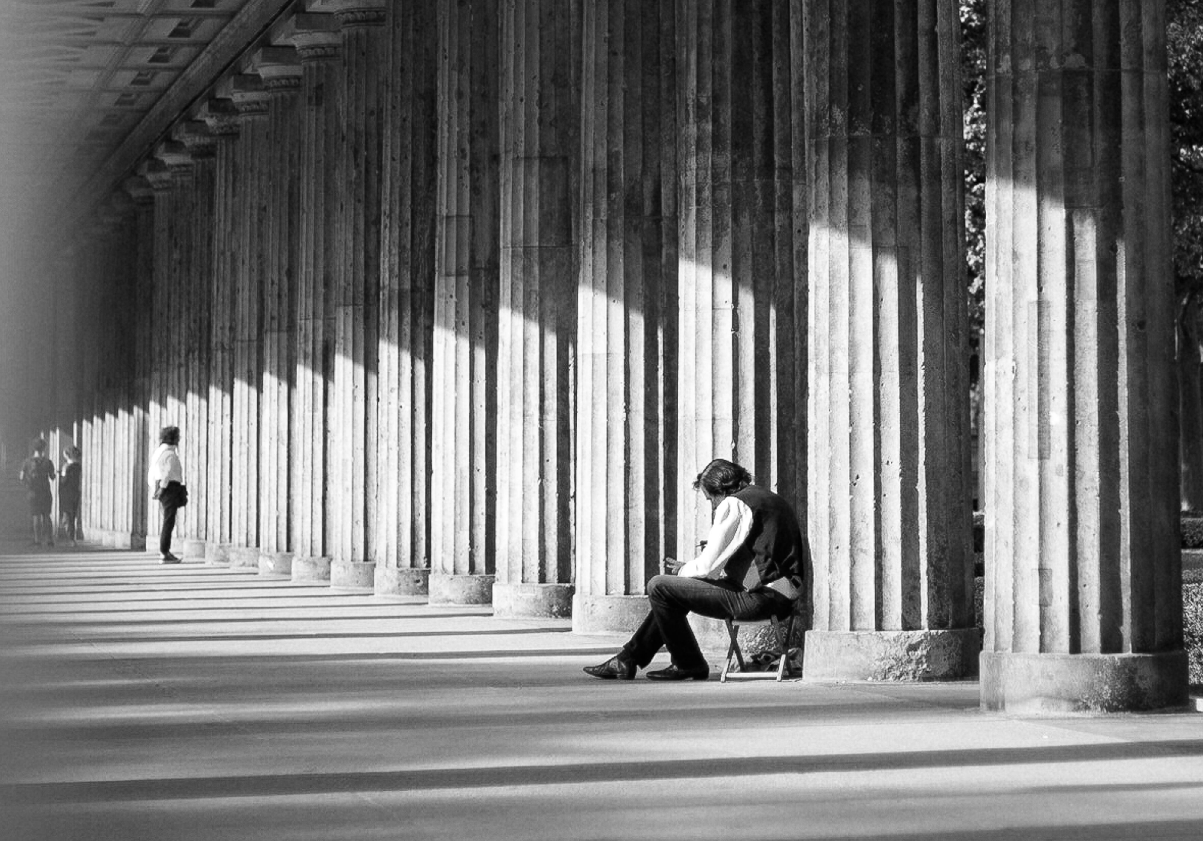 A man sitting on a bench under a column · Free Stock Photo
