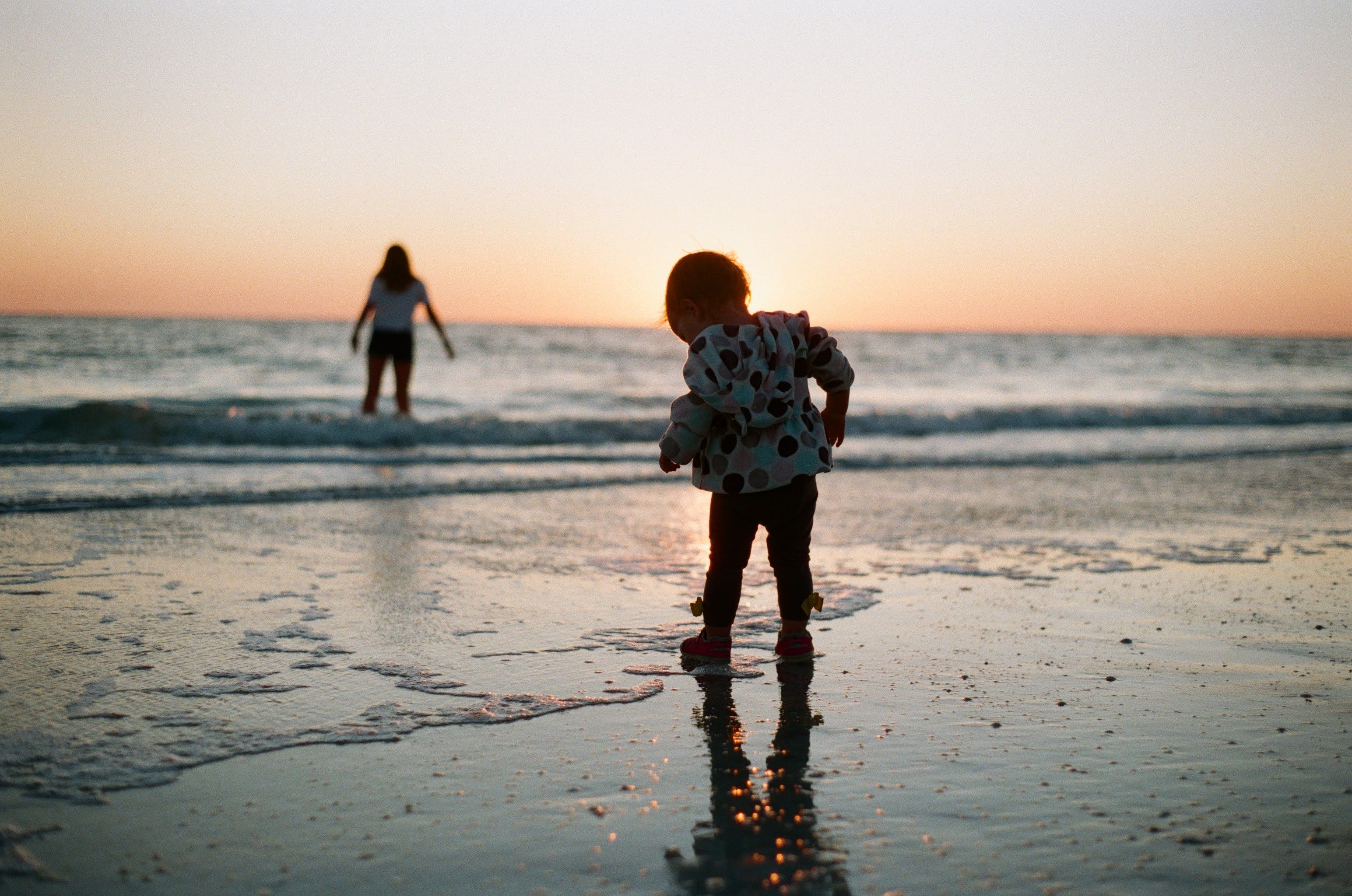 A child walking on the beach at sunset · Free Stock Photo