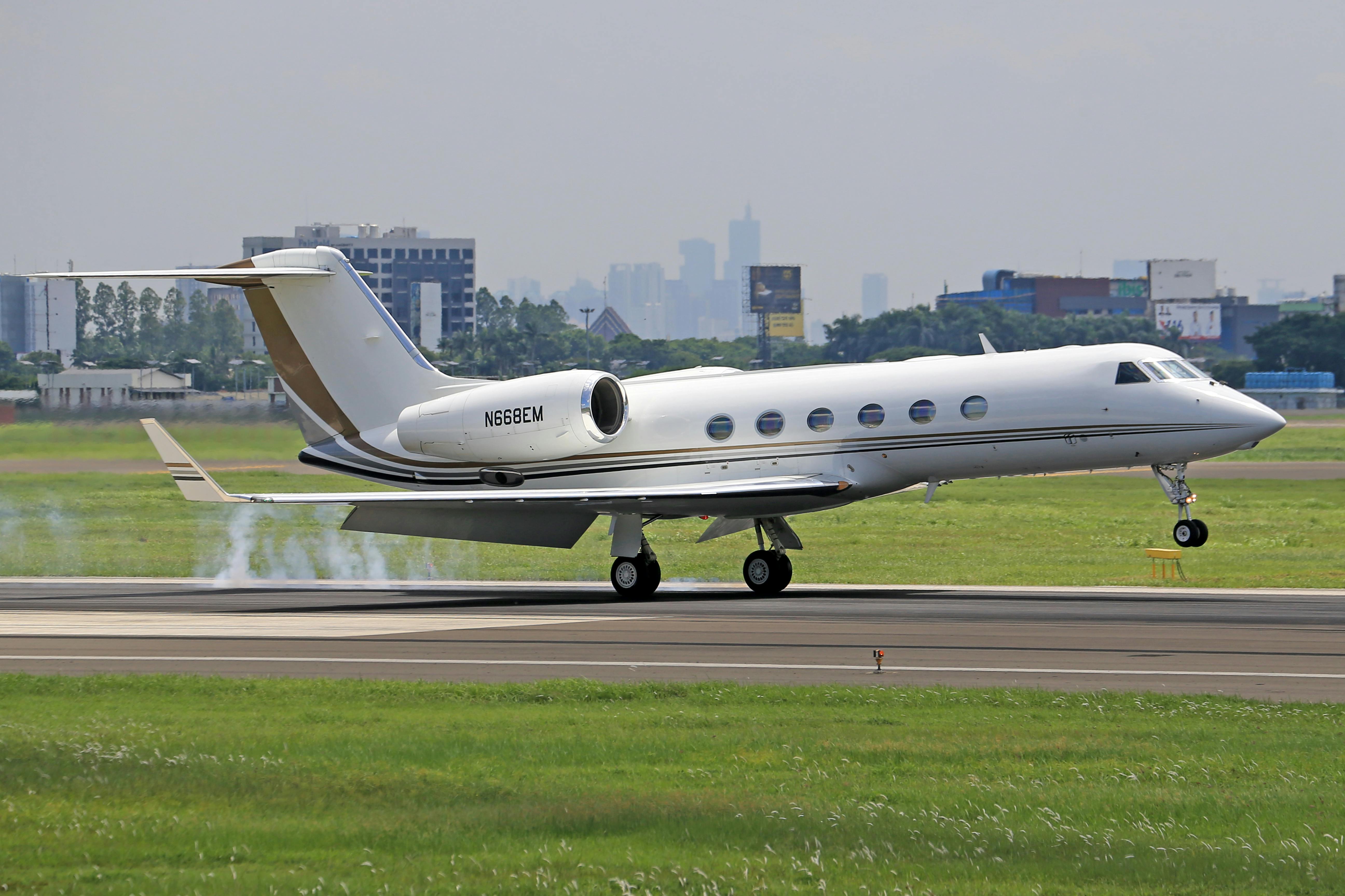 A white private jet taking off from an airport runway · Free Stock Photo