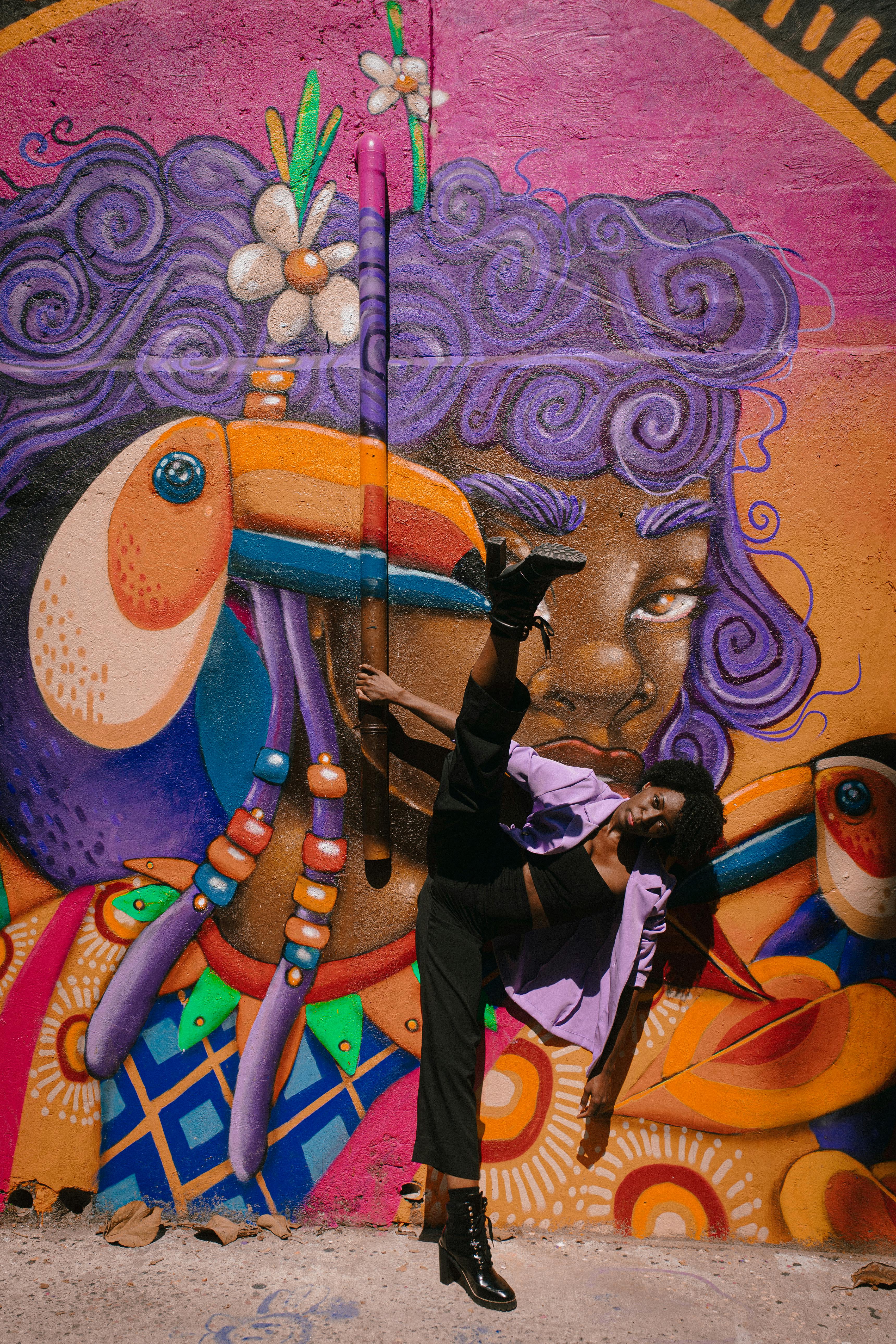 A man is standing on a pole in front of a colorful mural · Free Stock Photo