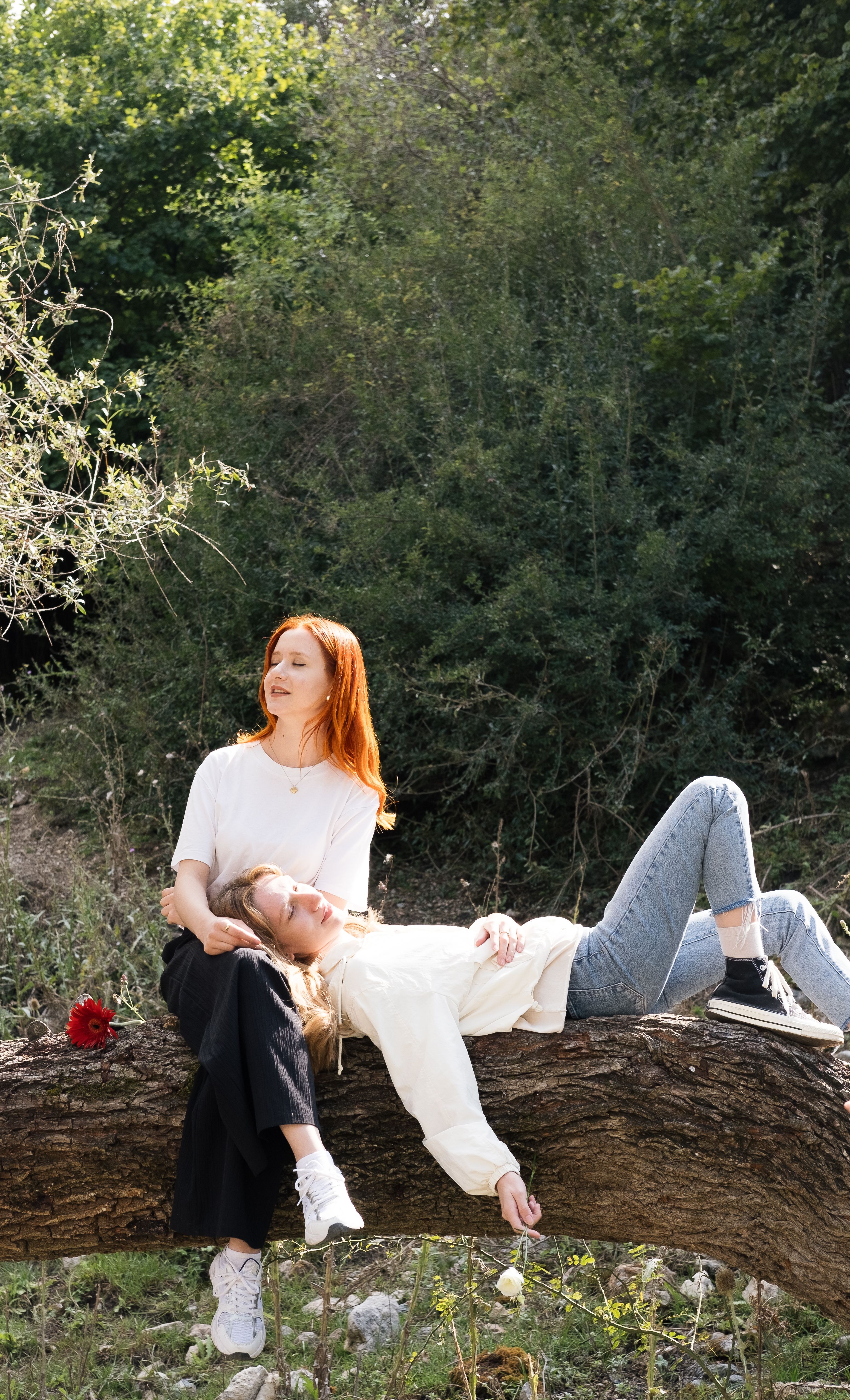 Two women laying on a tree branch · Free Stock Photo
