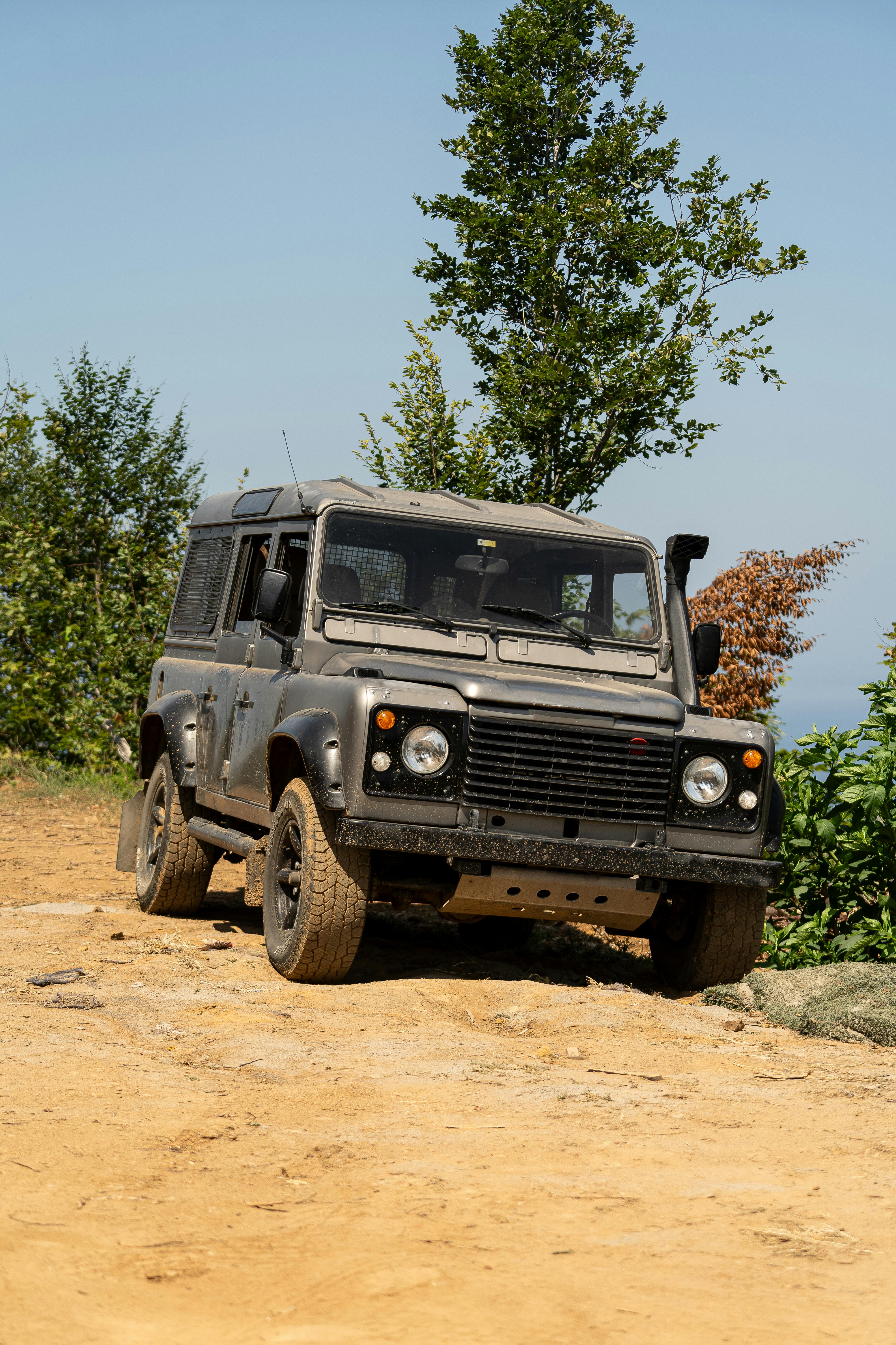 A Land Rover Defender Driving on a Dirt Road · Free Stock Photo