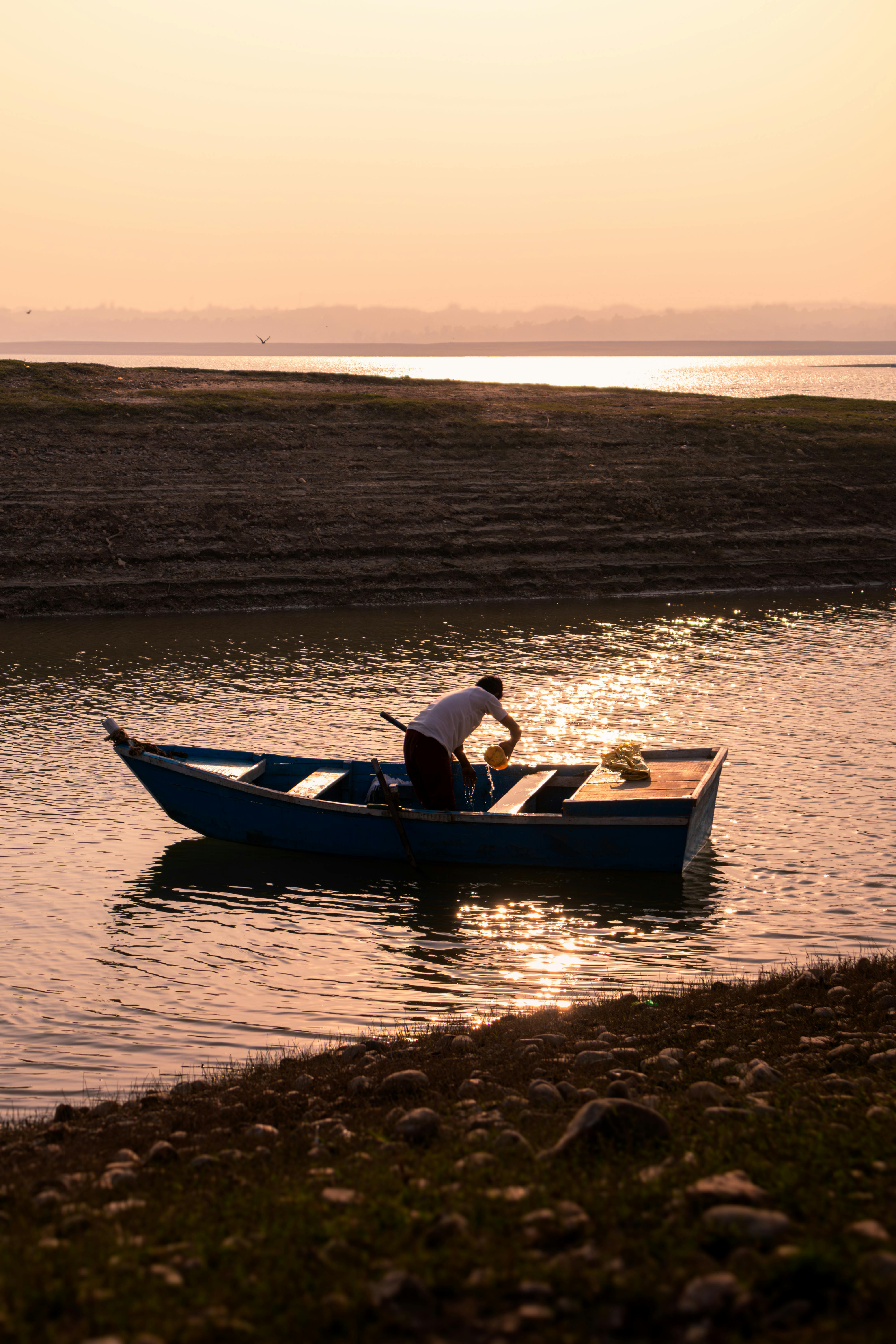 Man on Boat on Sea Shore at Sunset · Free Stock Photo