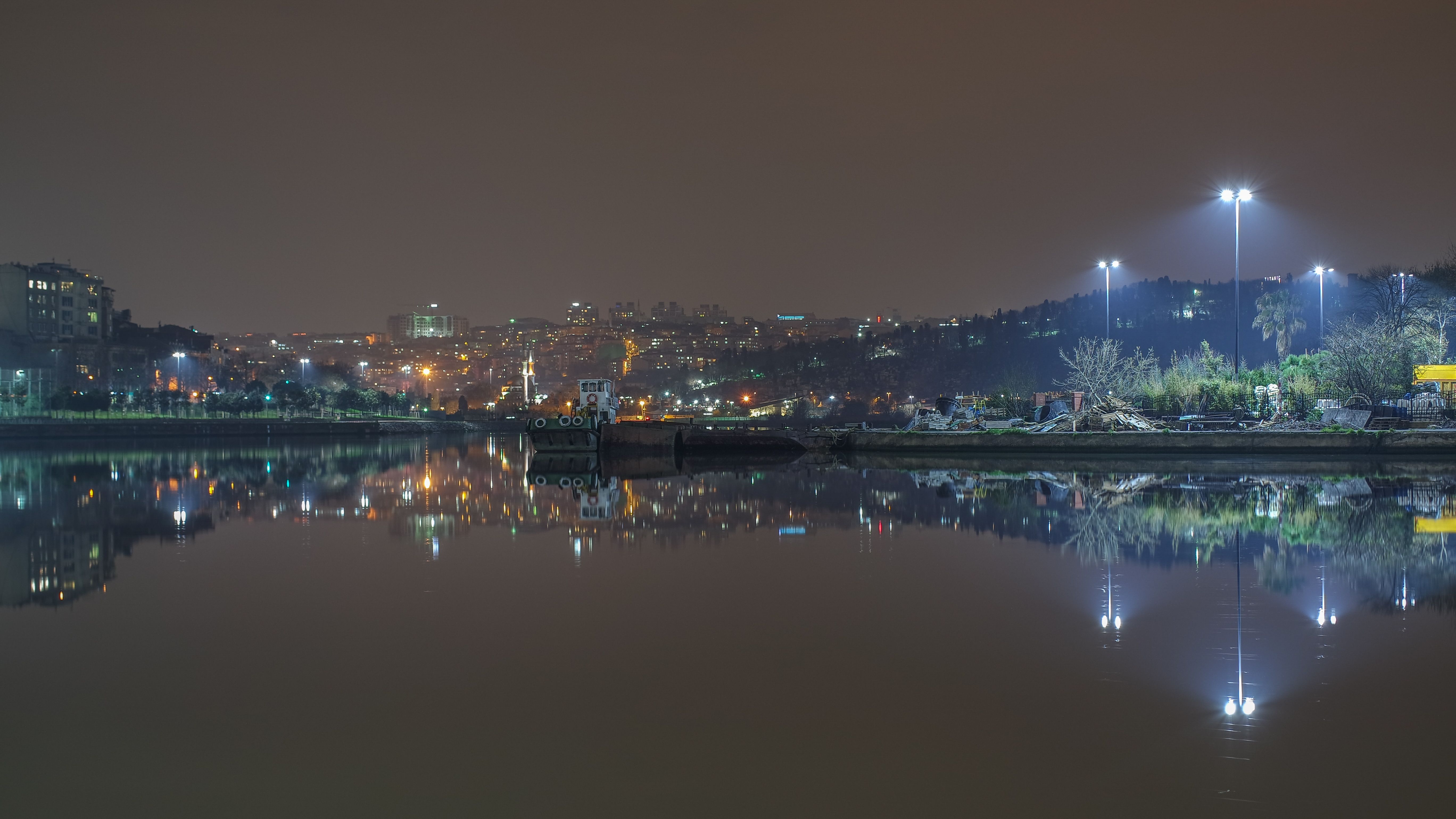 A city at night with lights reflecting in the water · Free Stock Photo