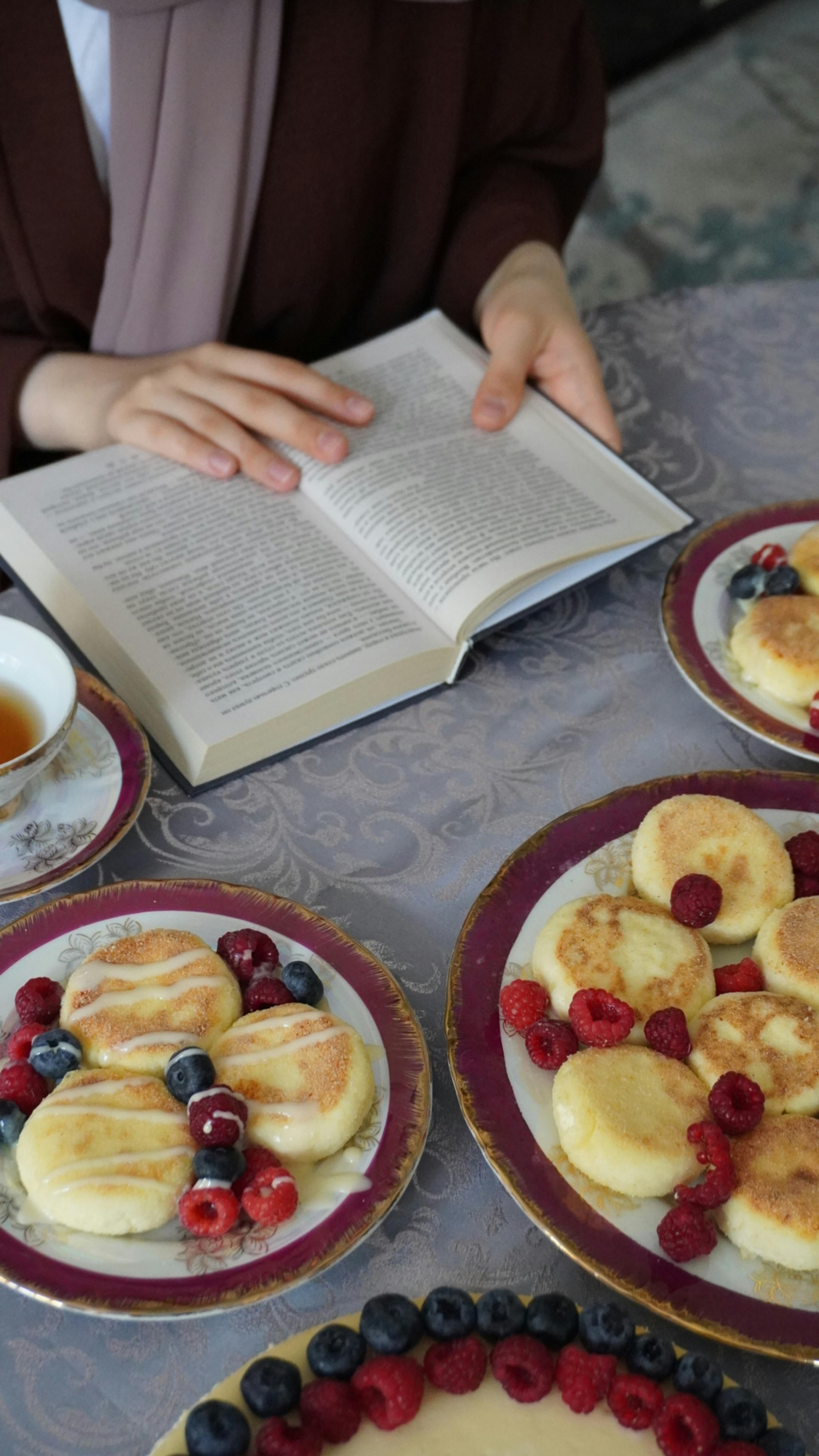 A woman is reading a book while eating pancakes · Free Stock Photo