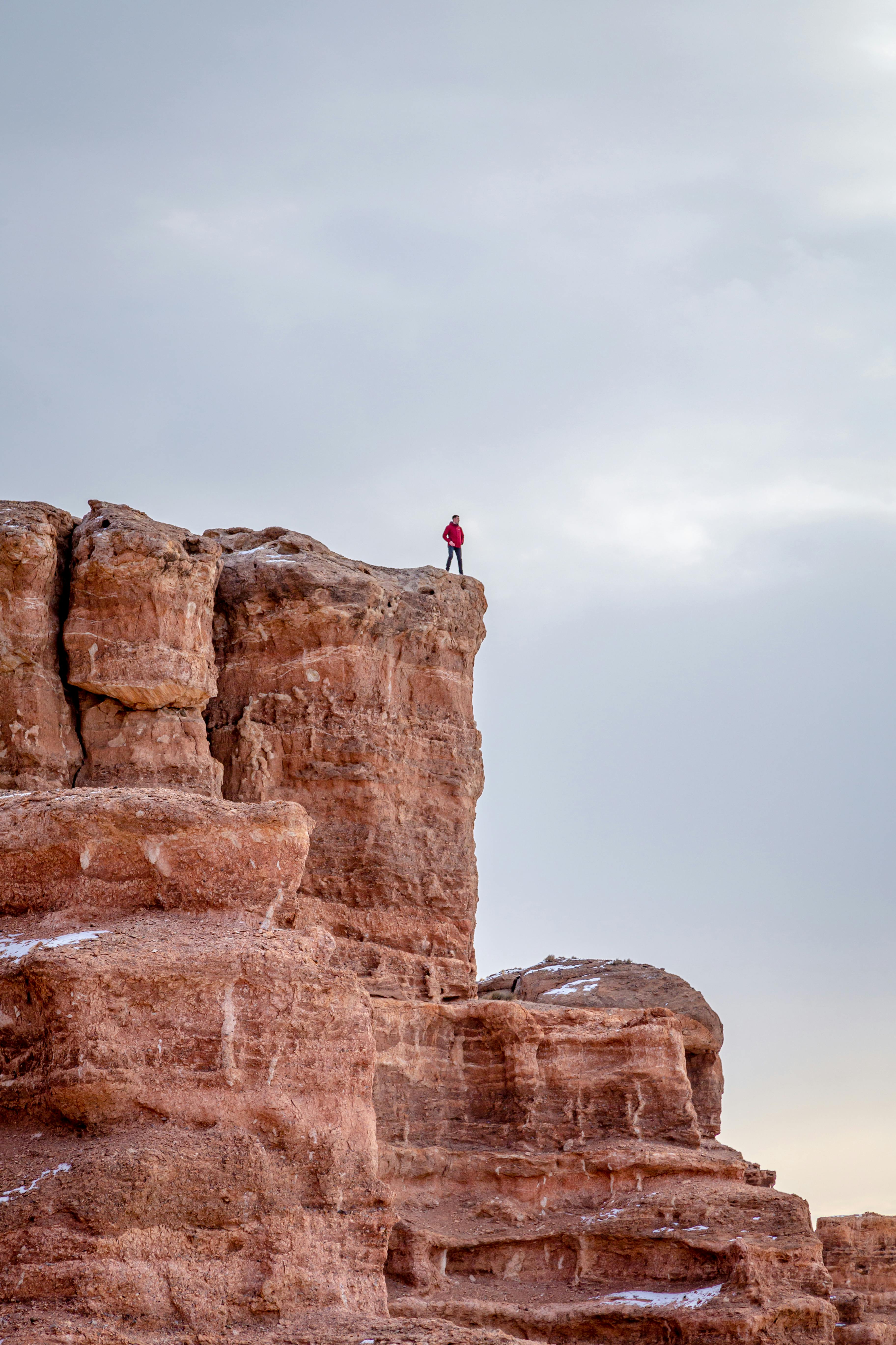 Person Standing on Top of Cliff in Canyon · Free Stock Photo