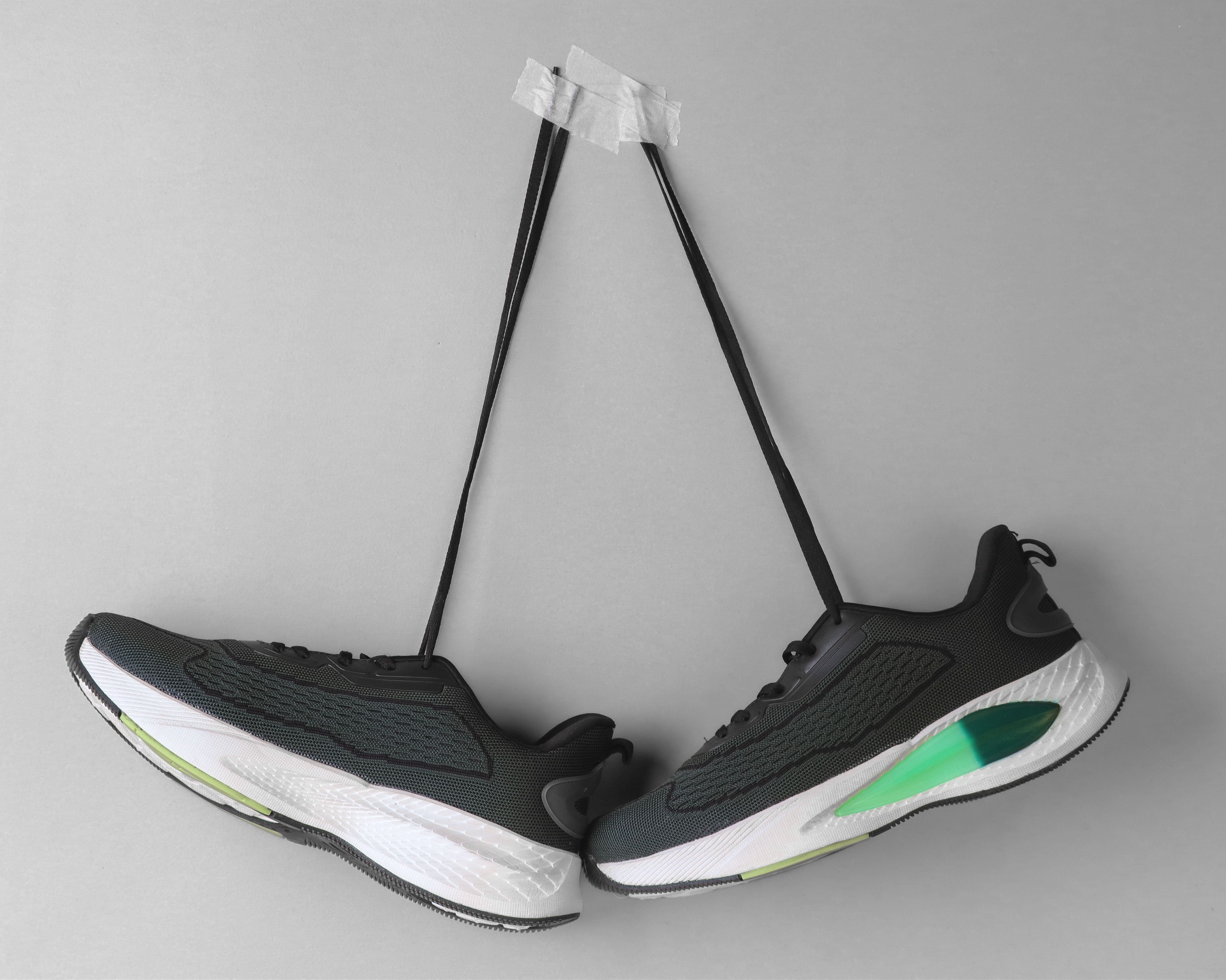 Modern Running Shoes Hanging on Grey Wall · Free Stock Photo