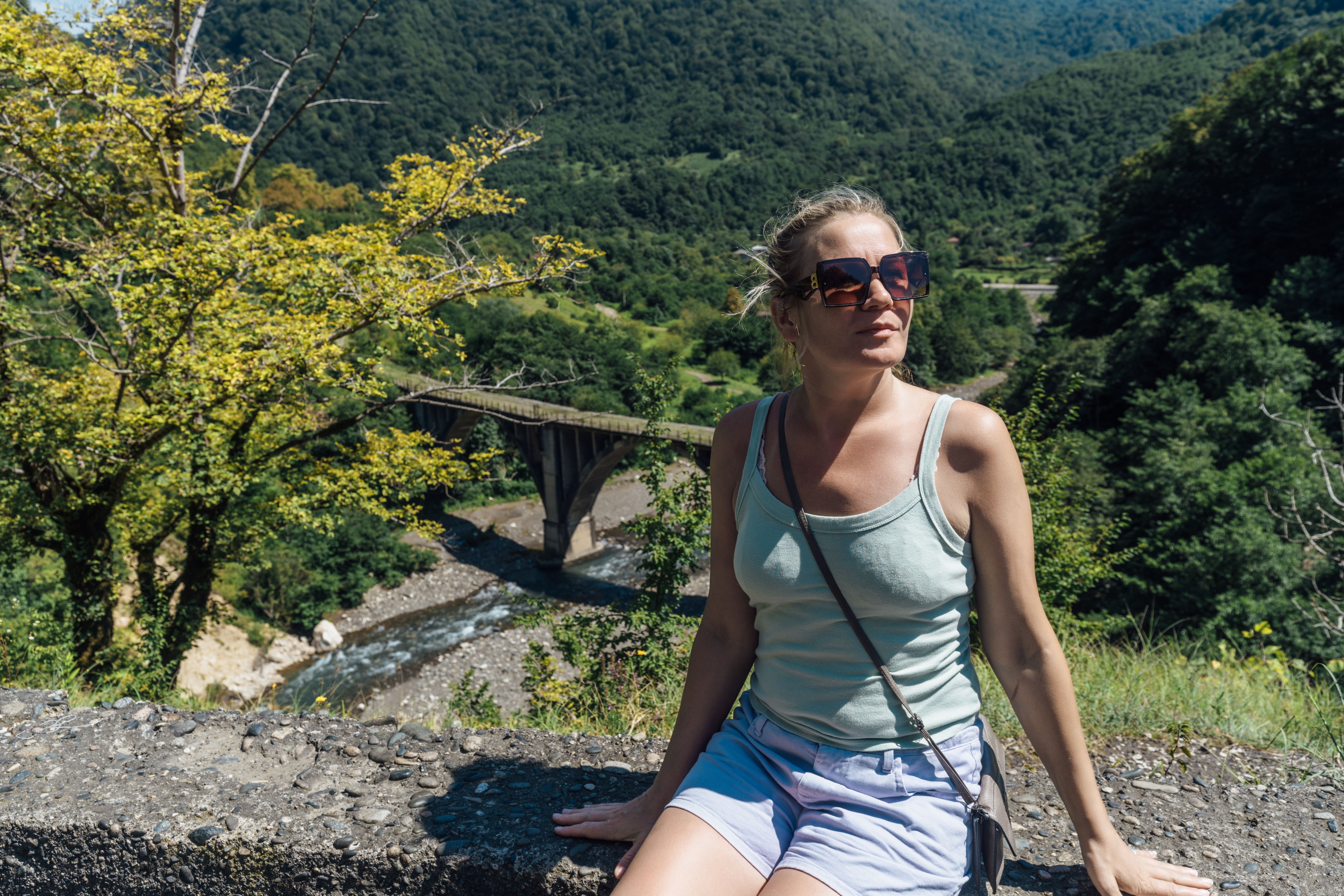 A woman sitting on a ledge overlooking a river · Free Stock Photo