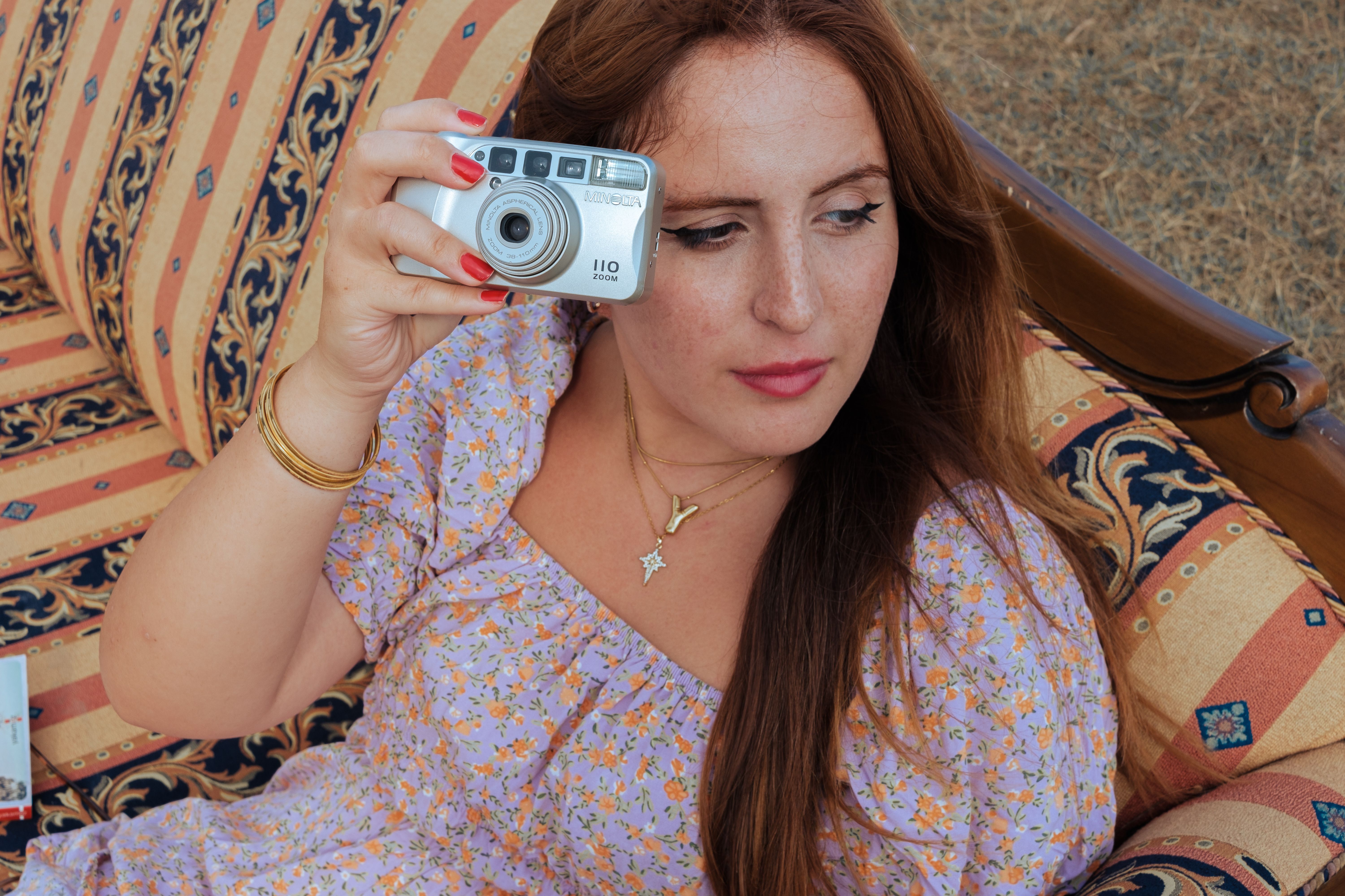 A woman is sitting on a couch holding a camera · Free Stock Photo