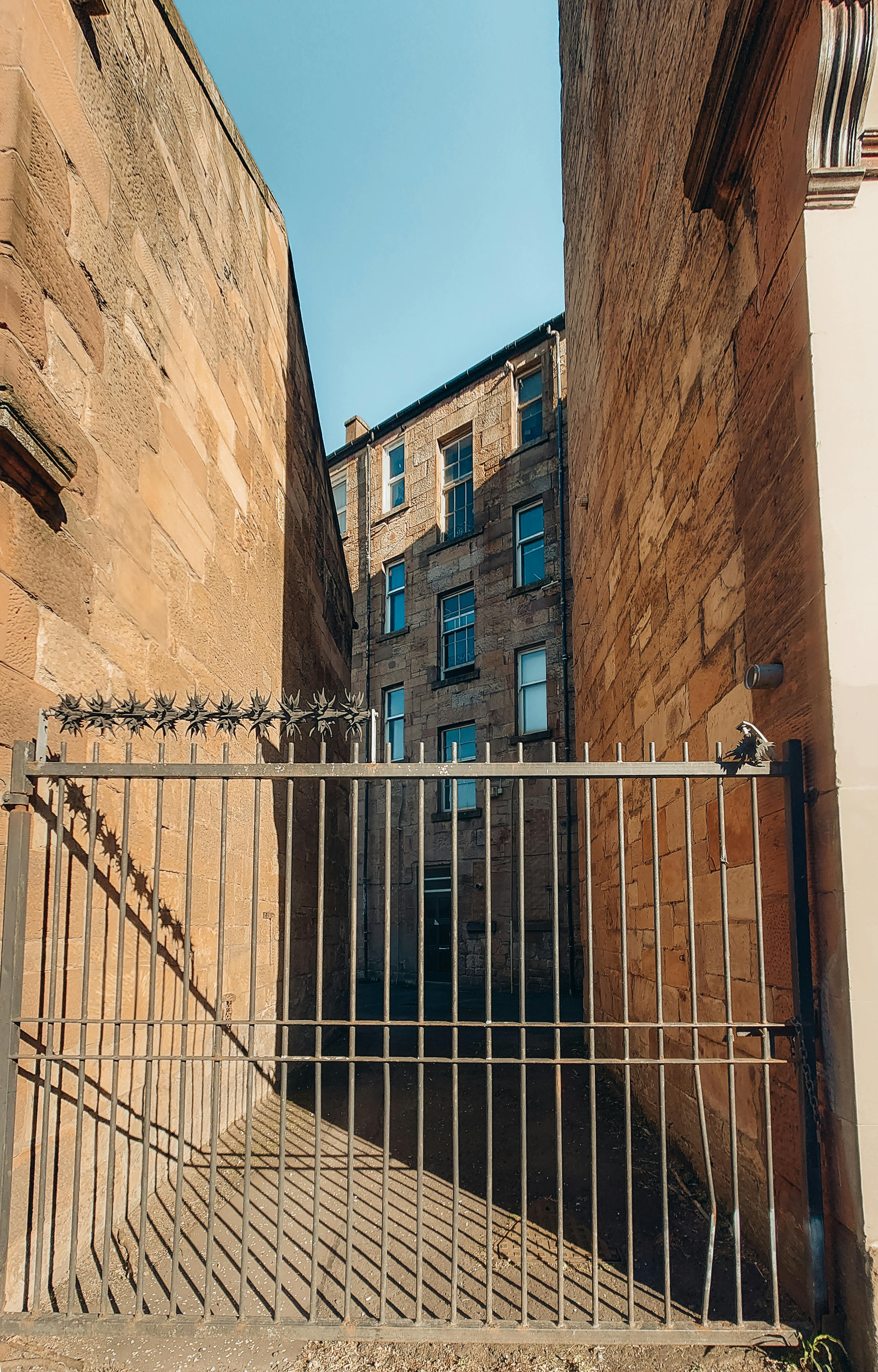 A gate in a narrow alleyway leading to a building · Free Stock Photo