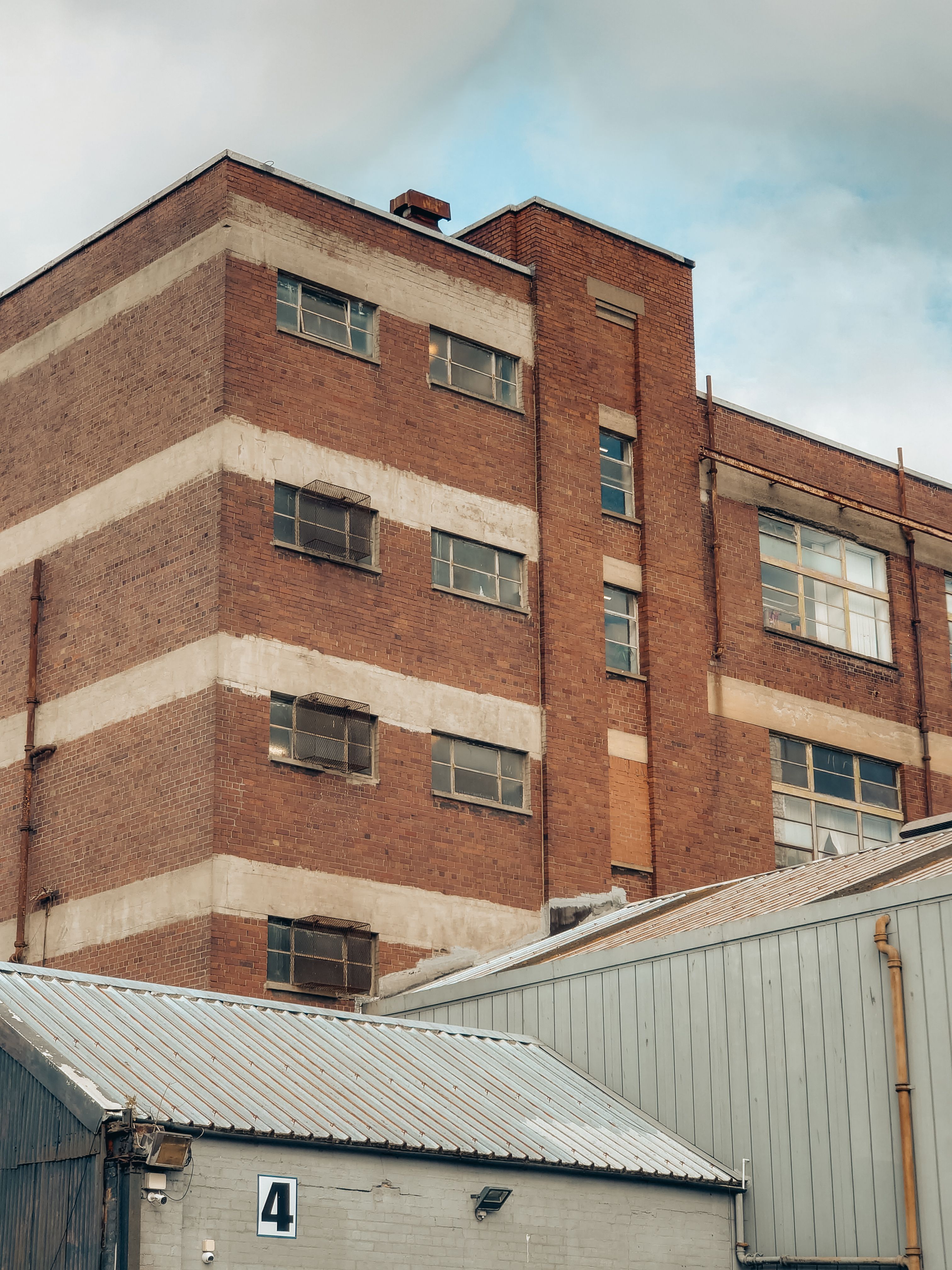 A building with a large brick wall and a roof · Free Stock Photo