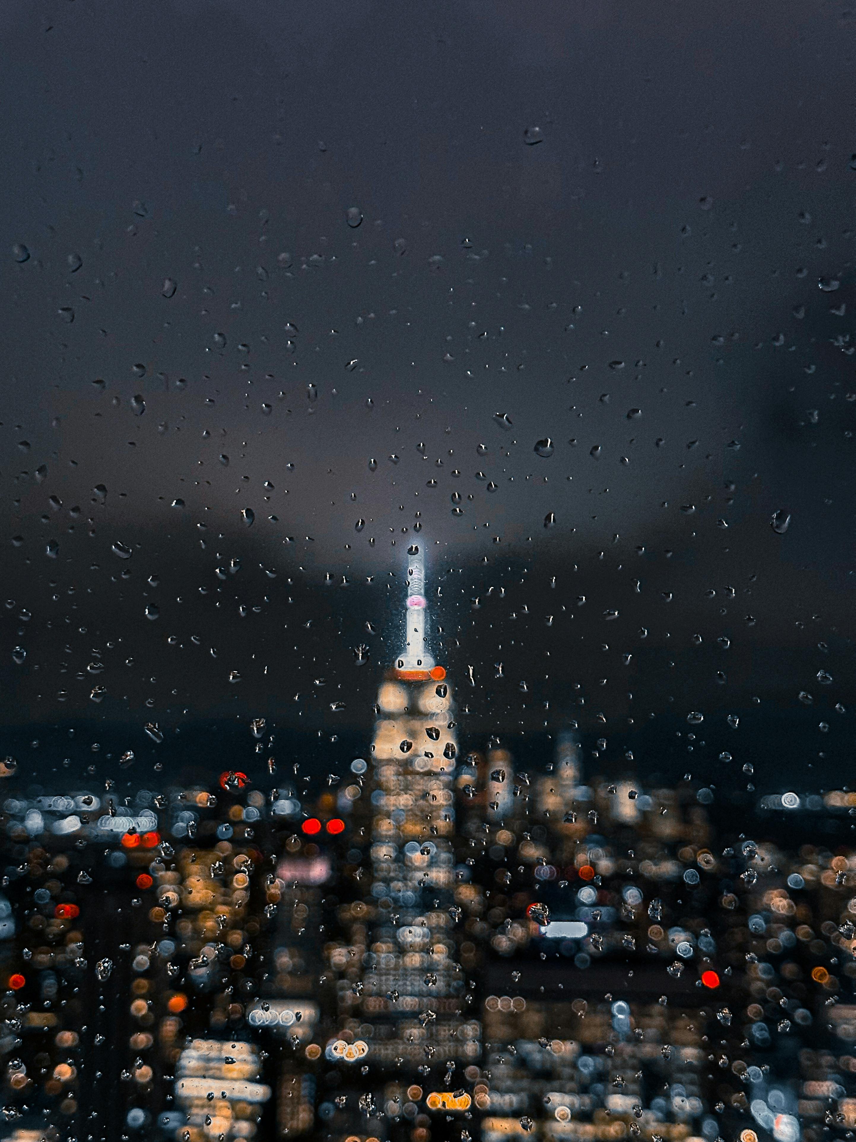 A city skyline is seen through a rain covered window · Free Stock Photo