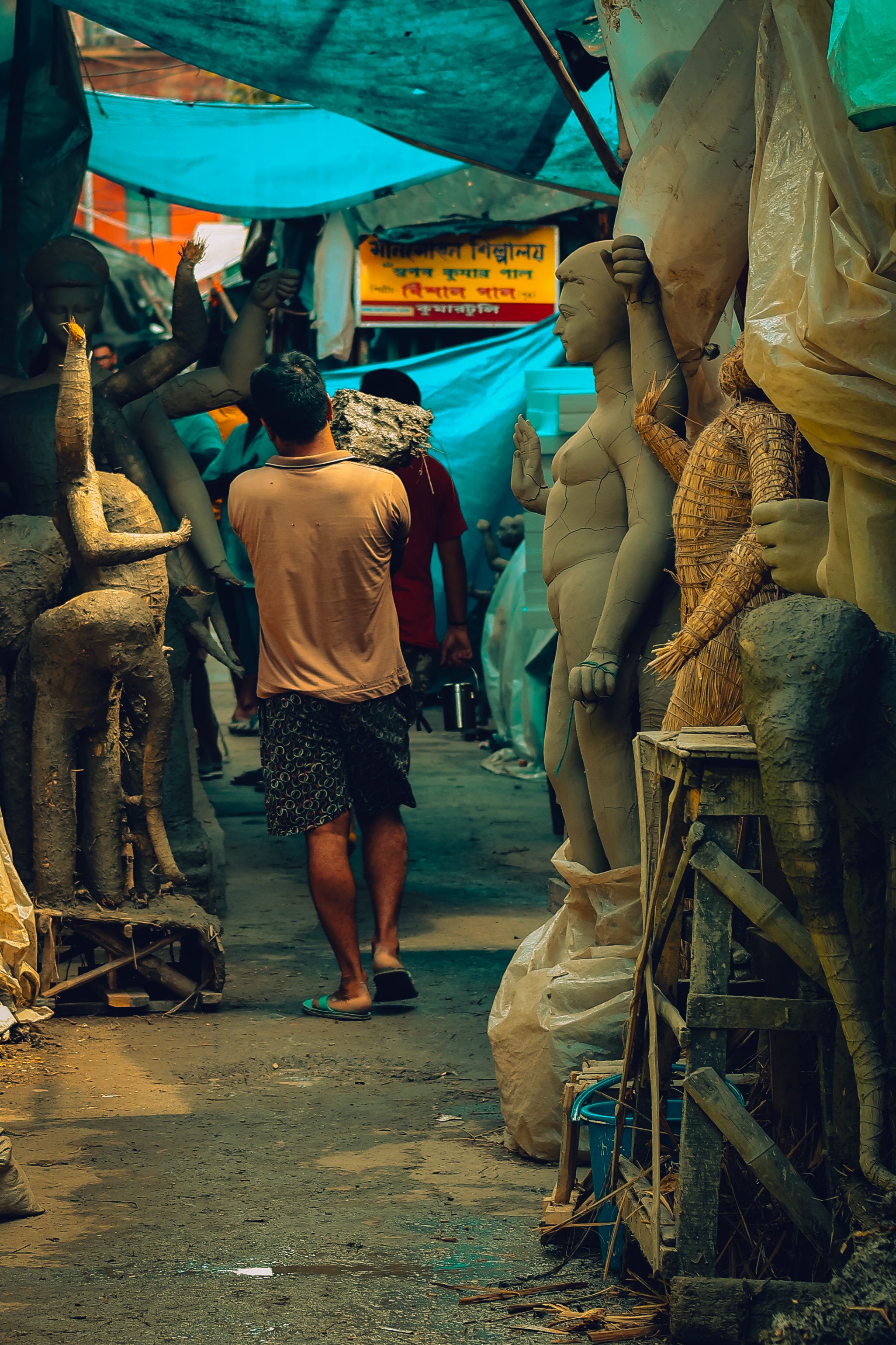 A man walking through a market with a bunch of statues · Free Stock Photo