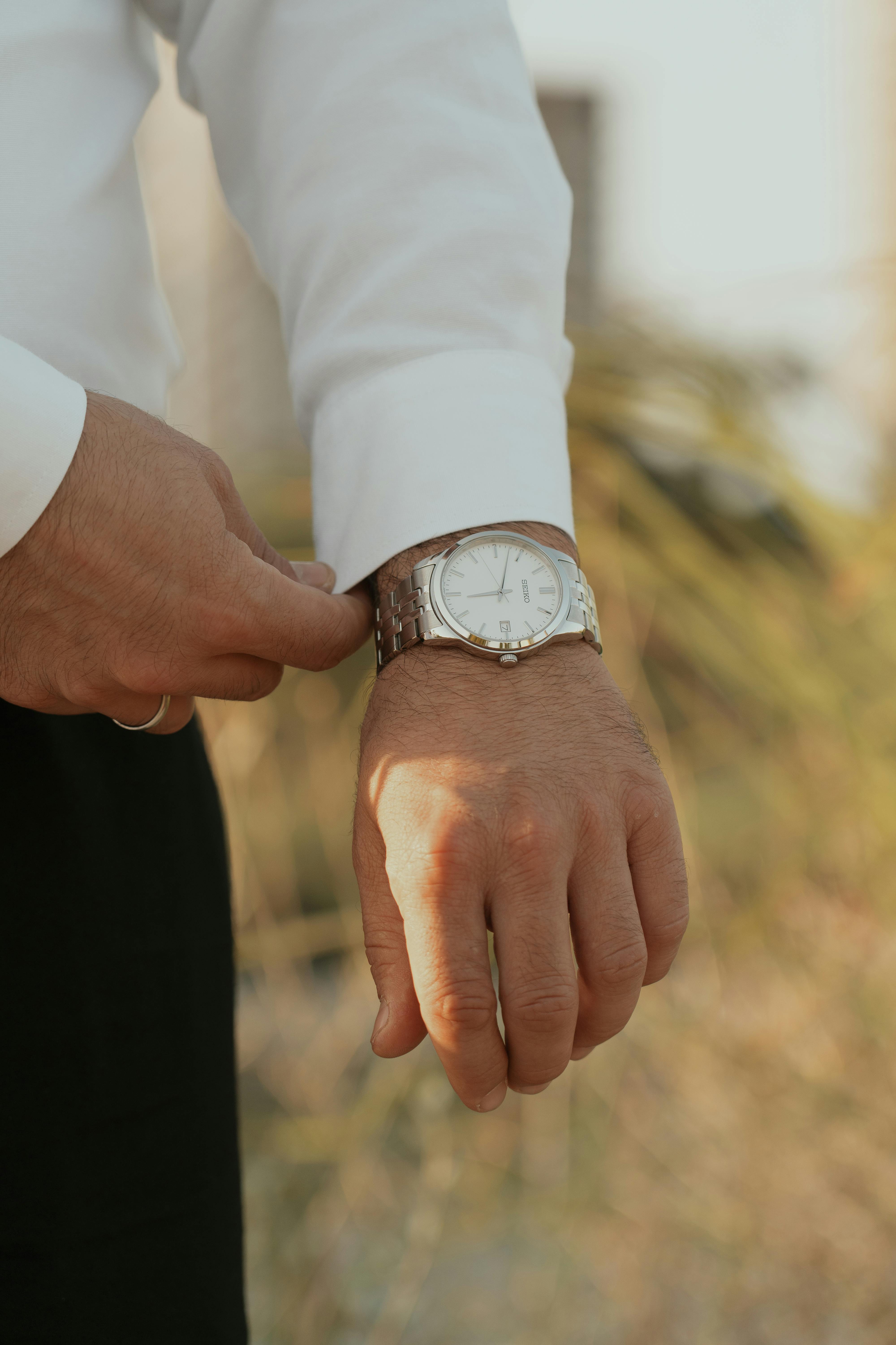 A man in a white shirt and black tie is adjusting his watch · Free ...