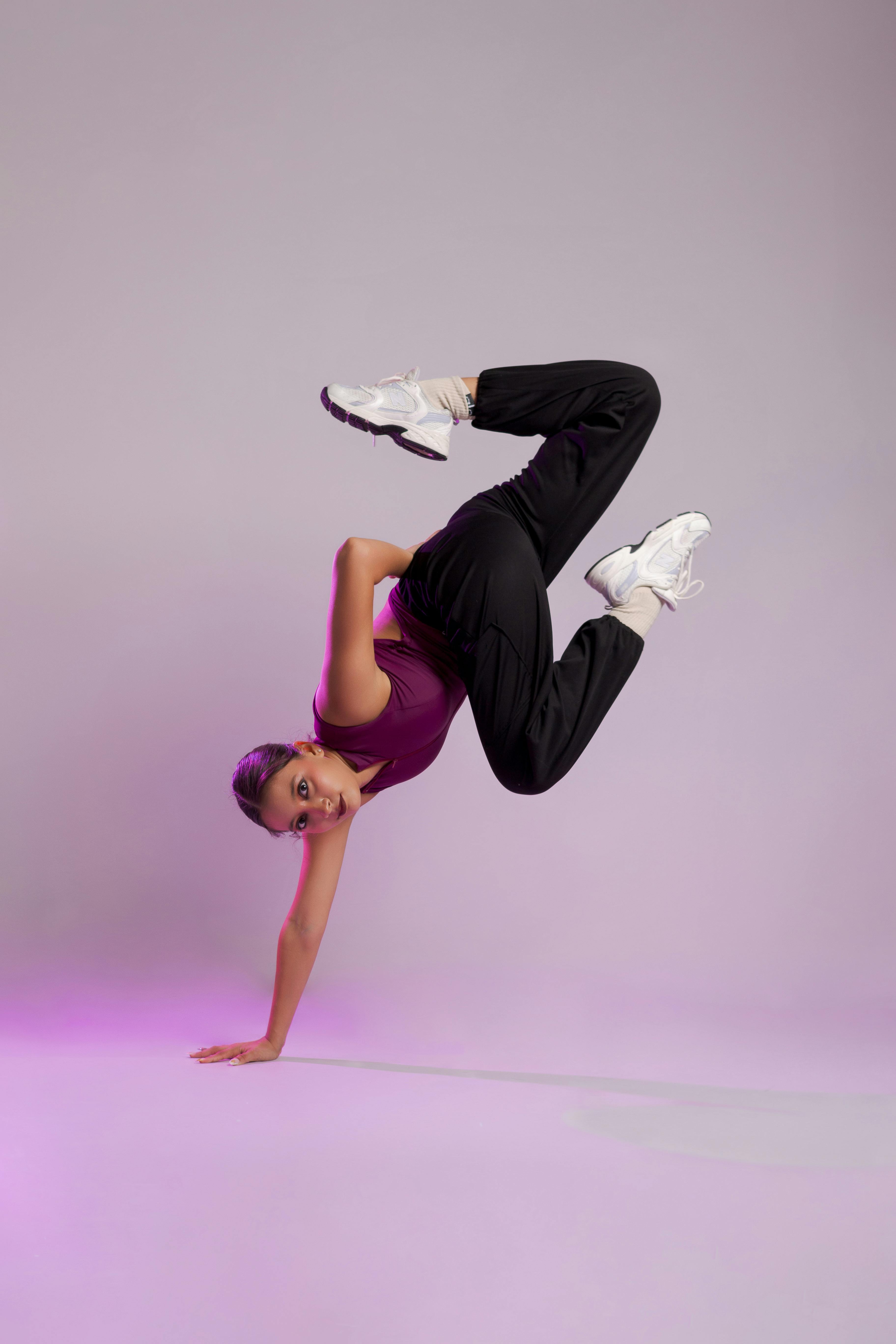 A young woman doing a handstand on a purple background · Free Stock Photo