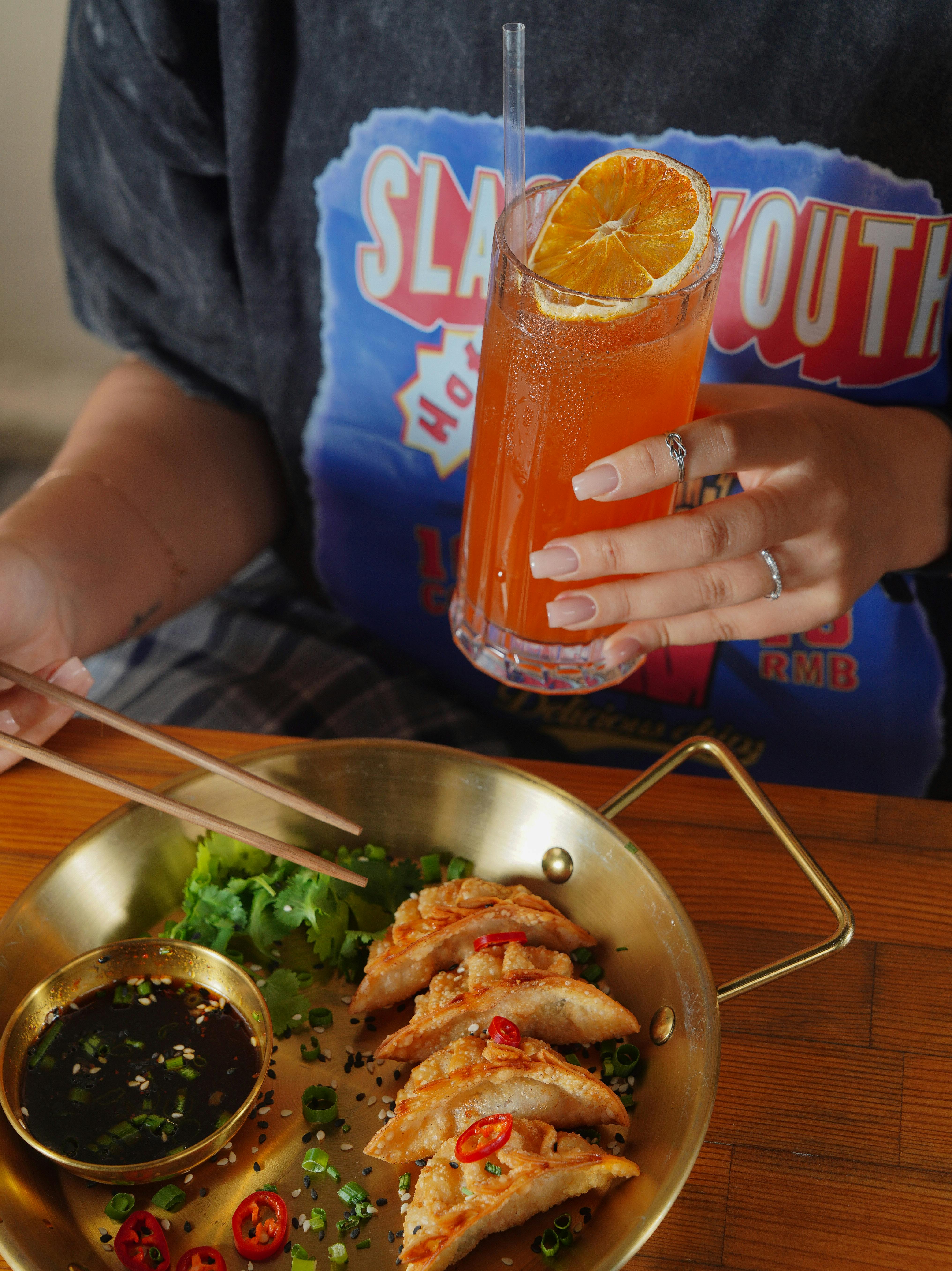 Person Enjoying Dumplings and Refreshing Cocktail · Free Stock Photo