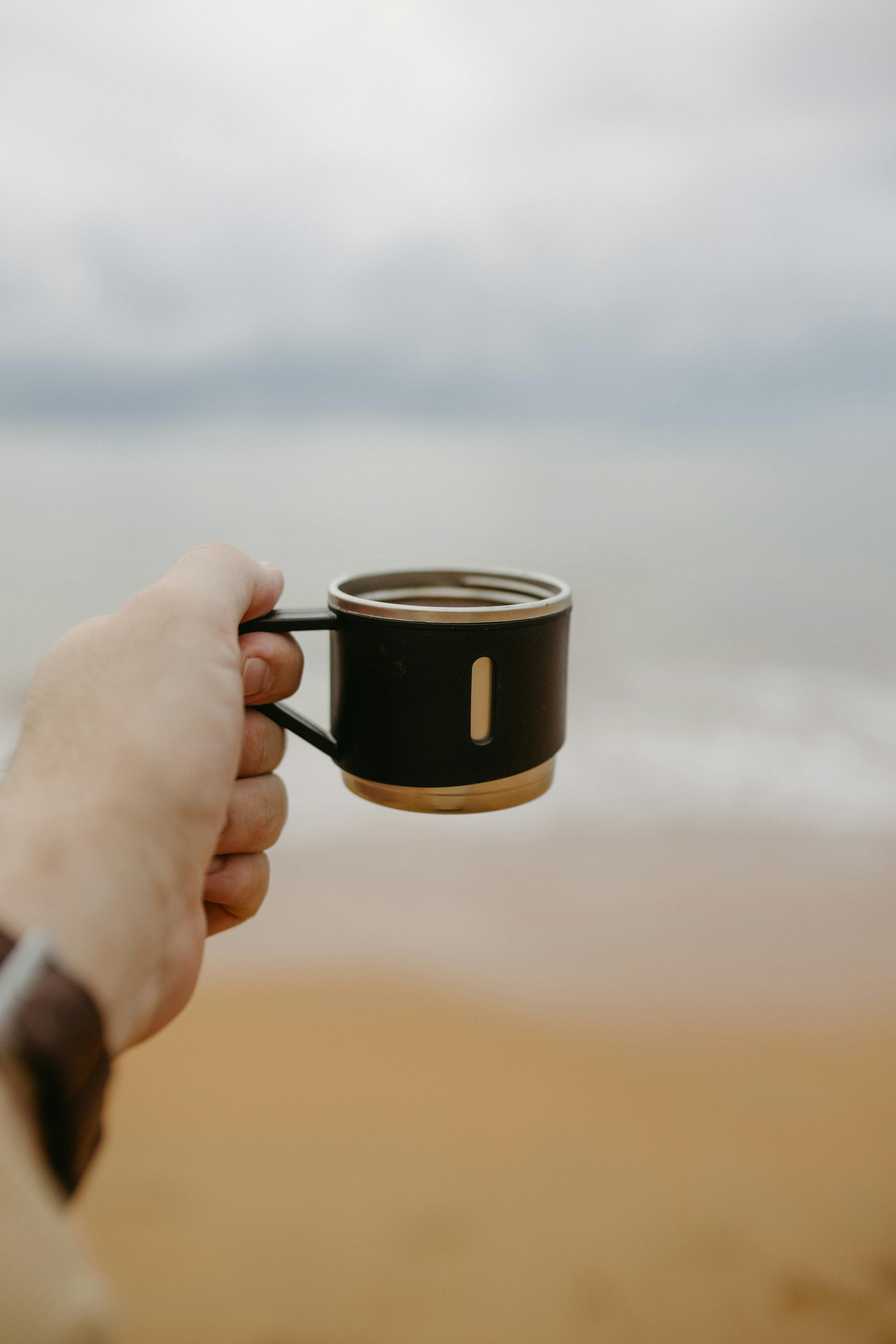 Hand Holding Coffee Mug at Beachfront View · Free Stock Photo