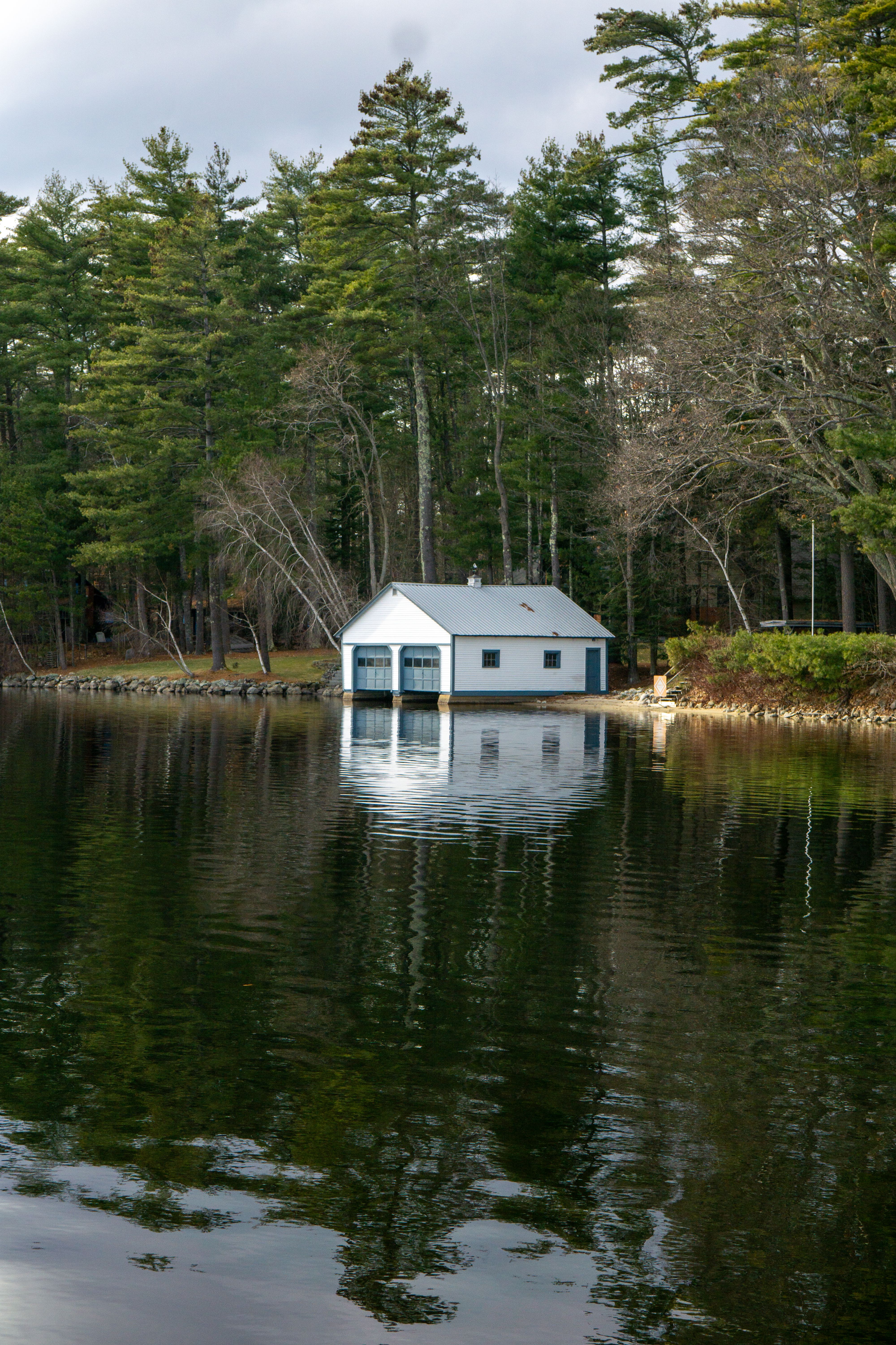 Tranquil Lakeside Boathouse Surrounded by Trees · Free Stock Photo