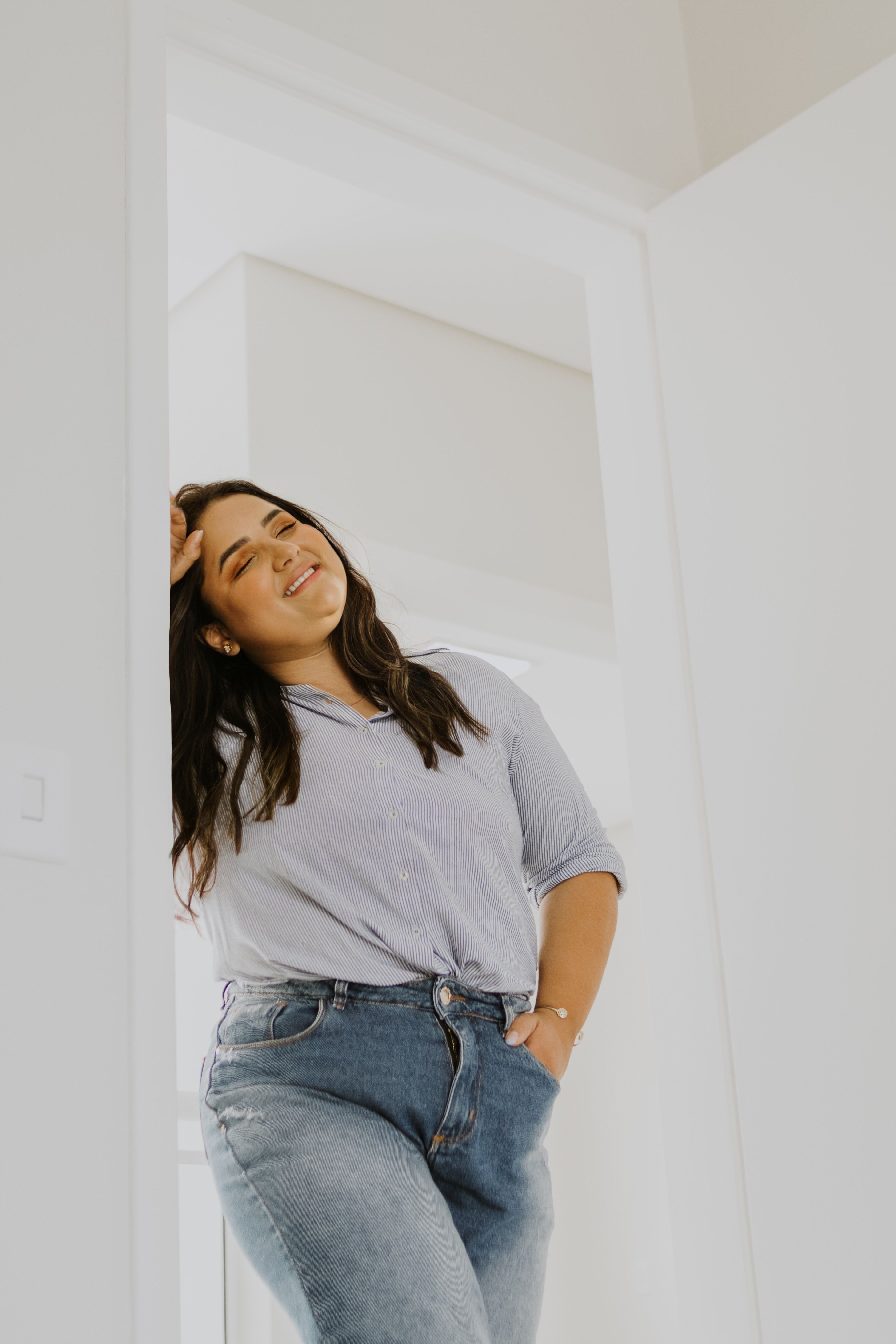 Smiling Woman Leaning in Doorframe Indoors · Free Stock Photo