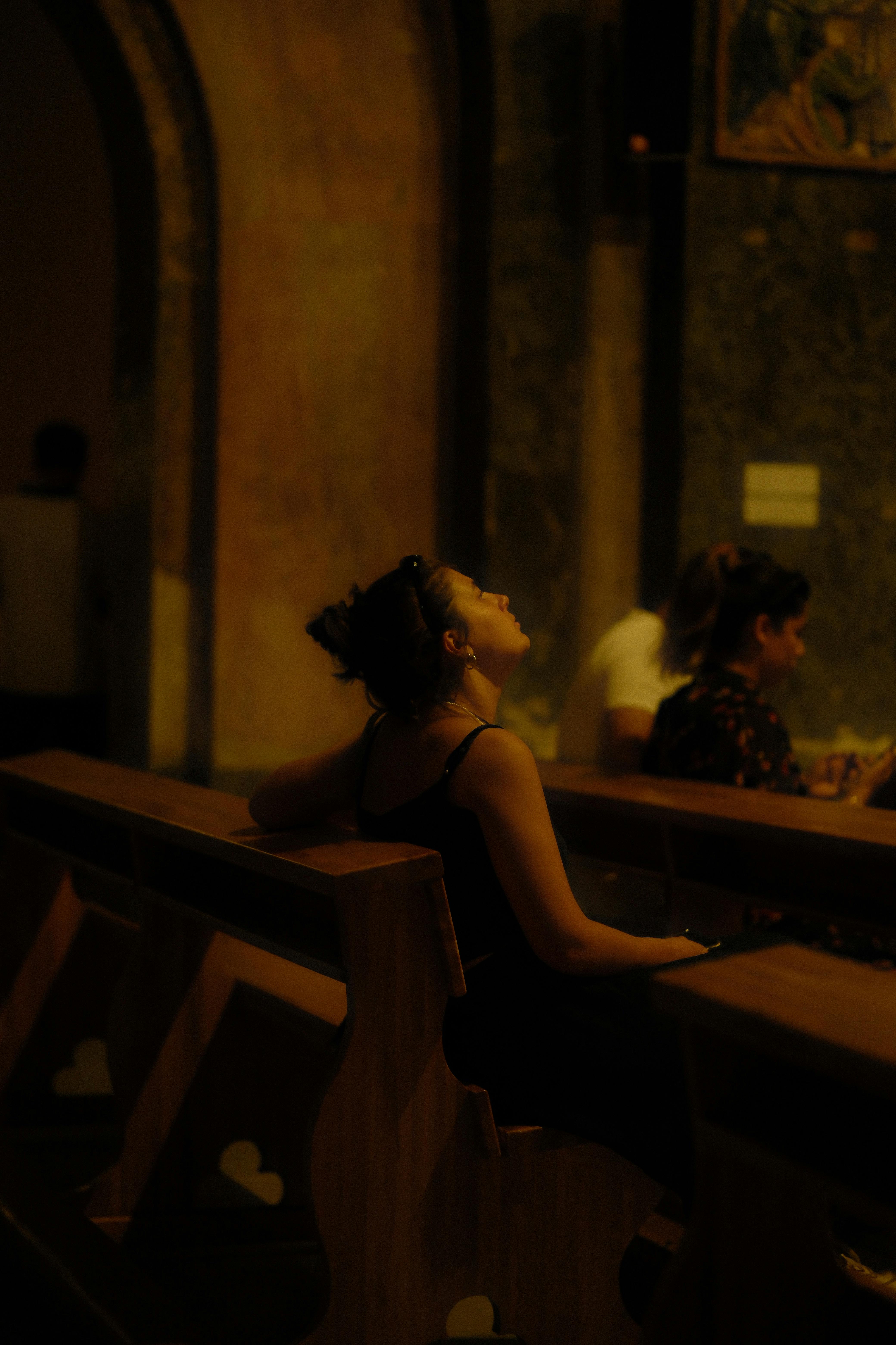 Contemplative Woman in Dimly Lit Church Interior · Free Stock Photo