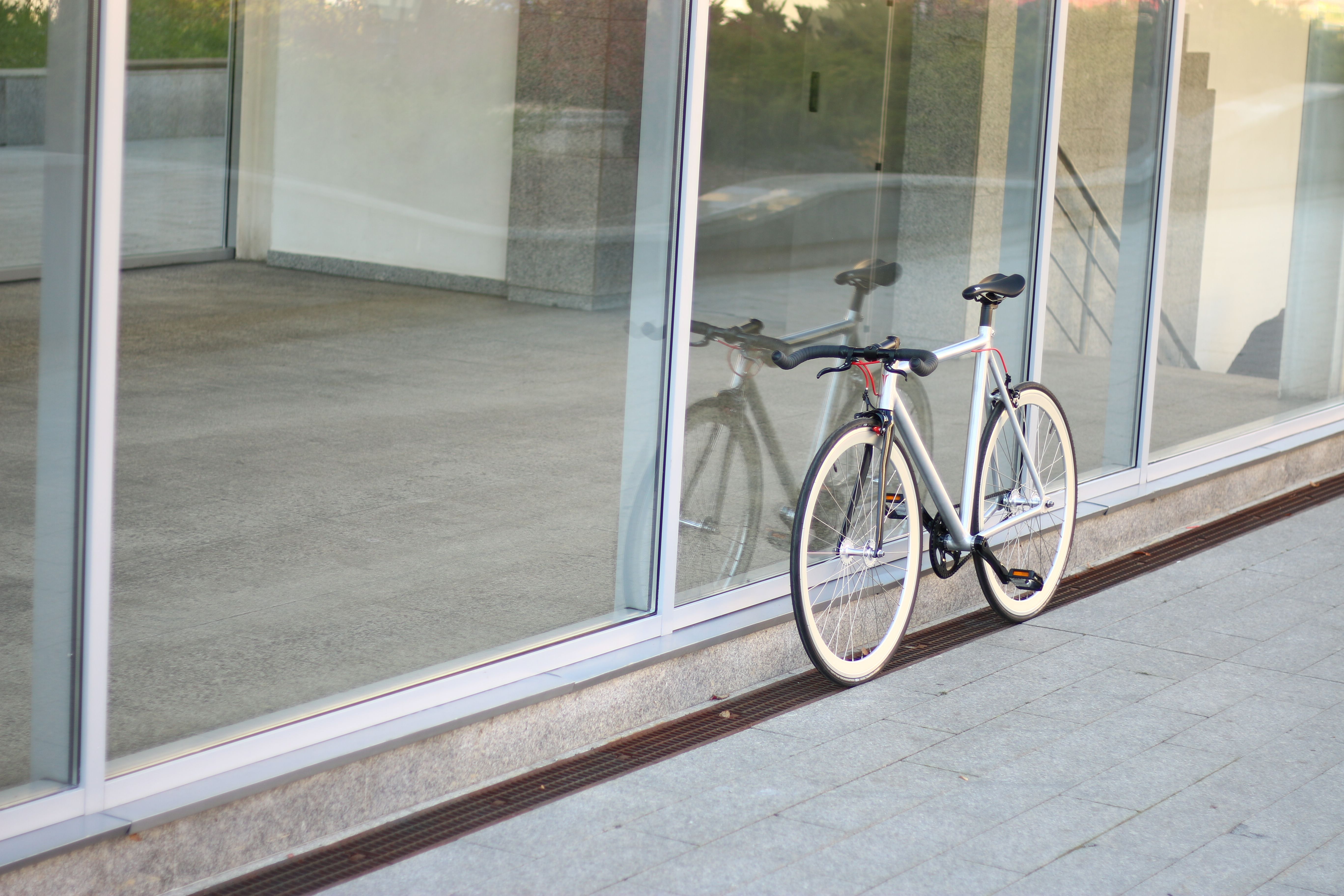 Modern Bicycle Leaning Against Glass Building · Free Stock Photo