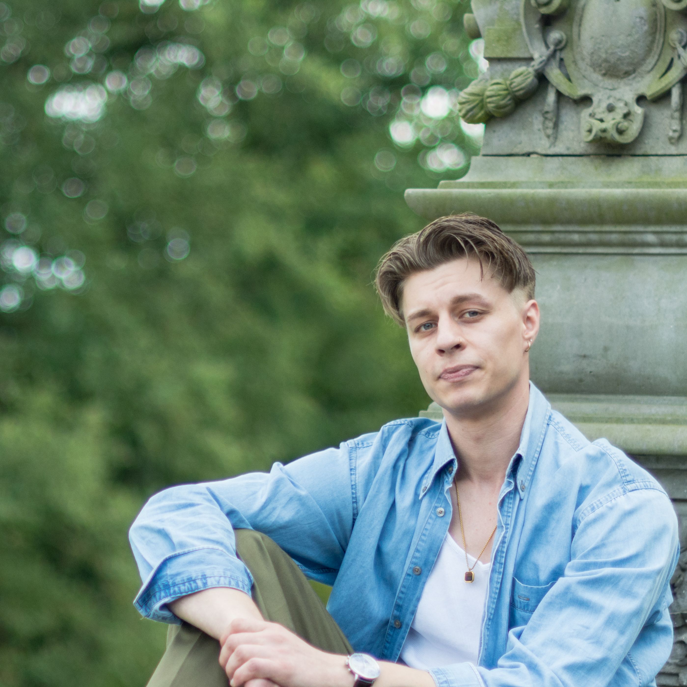 Young Man Relaxing Outdoors on Stone Structure · Free Stock Photo