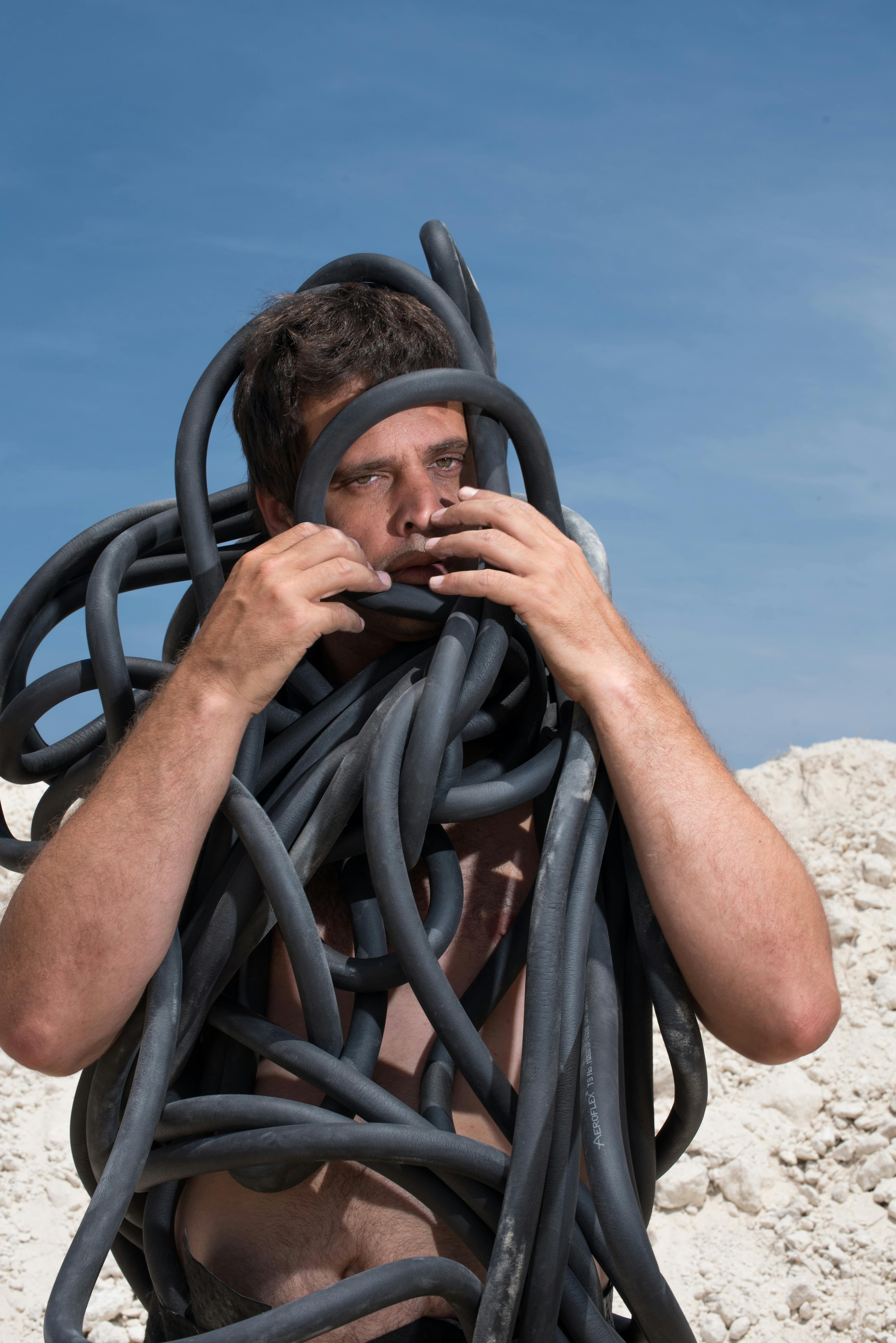 Man Entangled in Hoses Against Desert Background · Free Stock Photo
