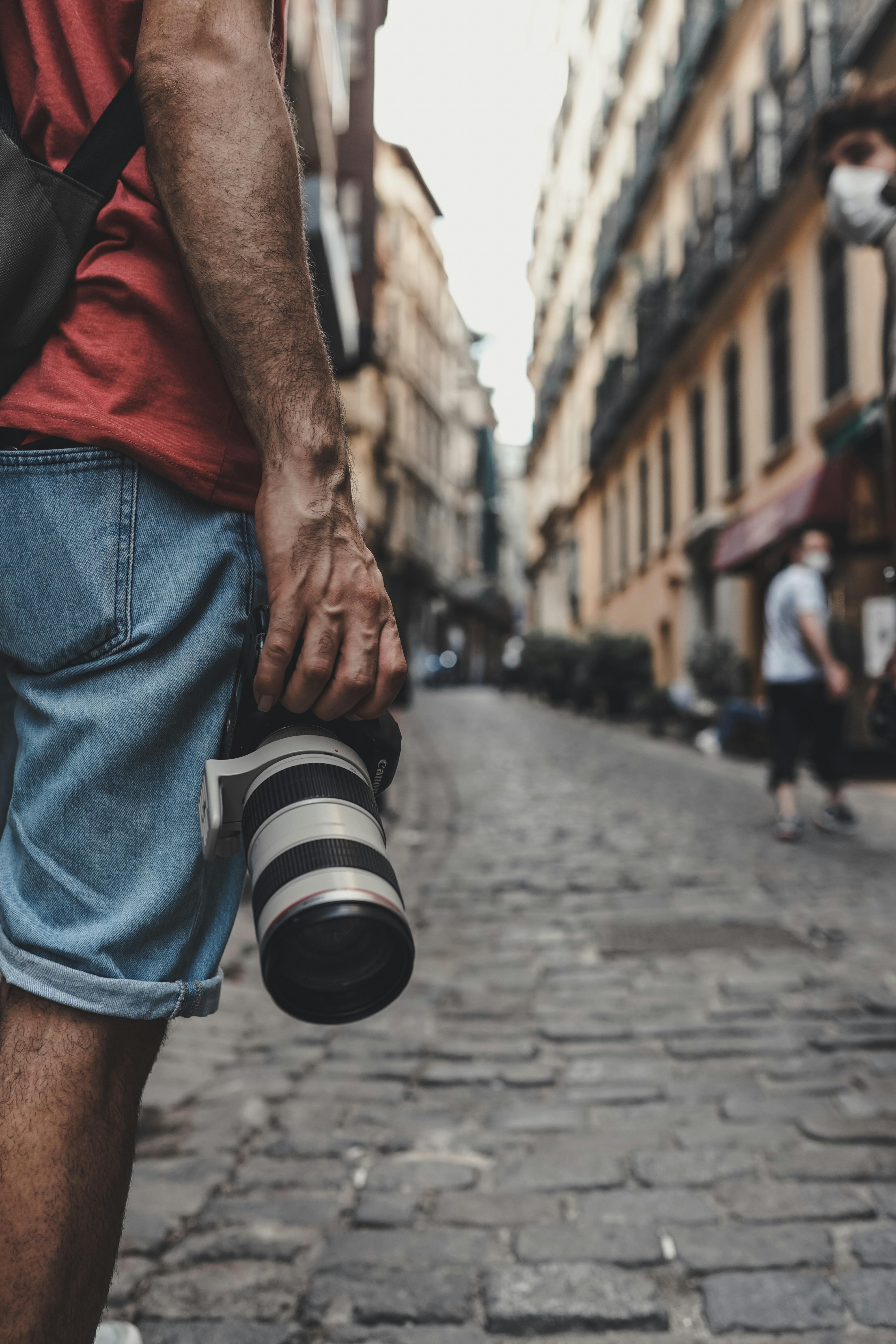 Man with camera walking down street · Free Stock Photo
