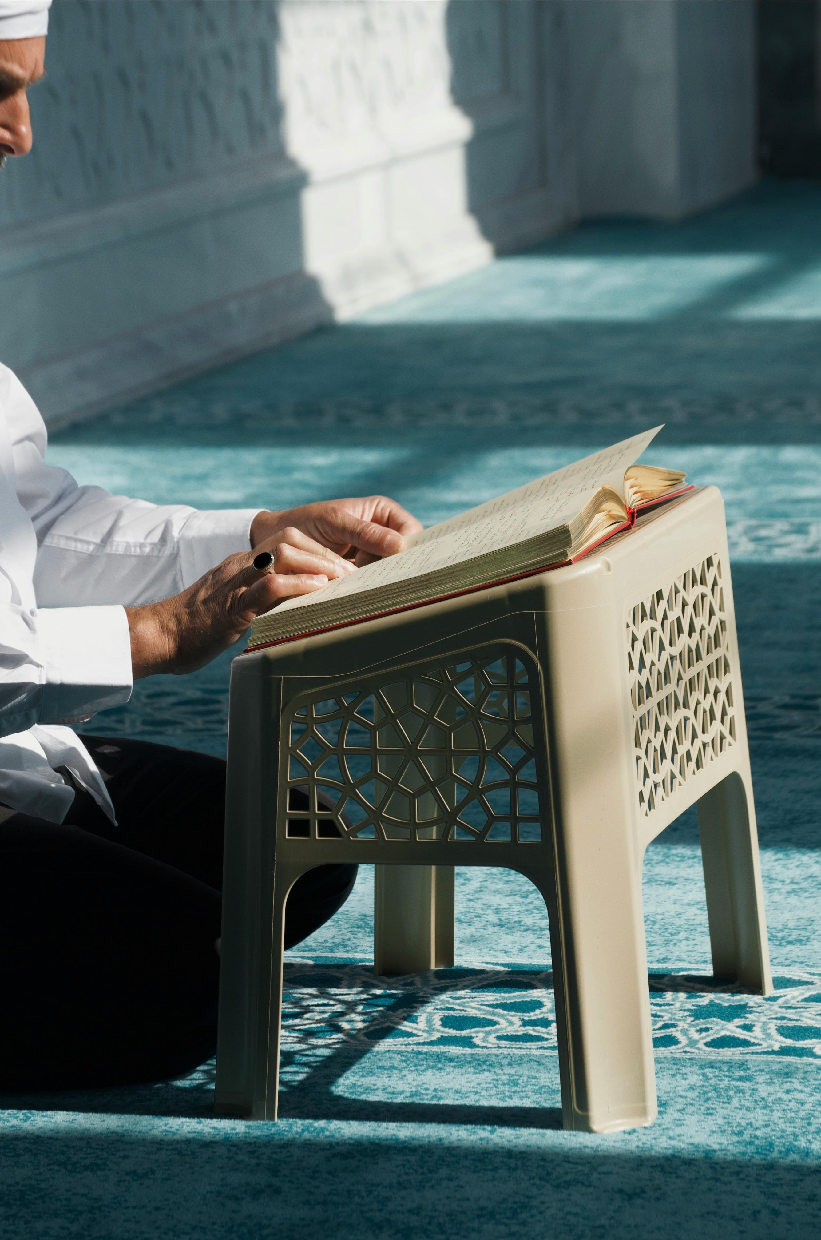 Man Reading Holy Book in Peaceful Mosque Setting · Free Stock Photo