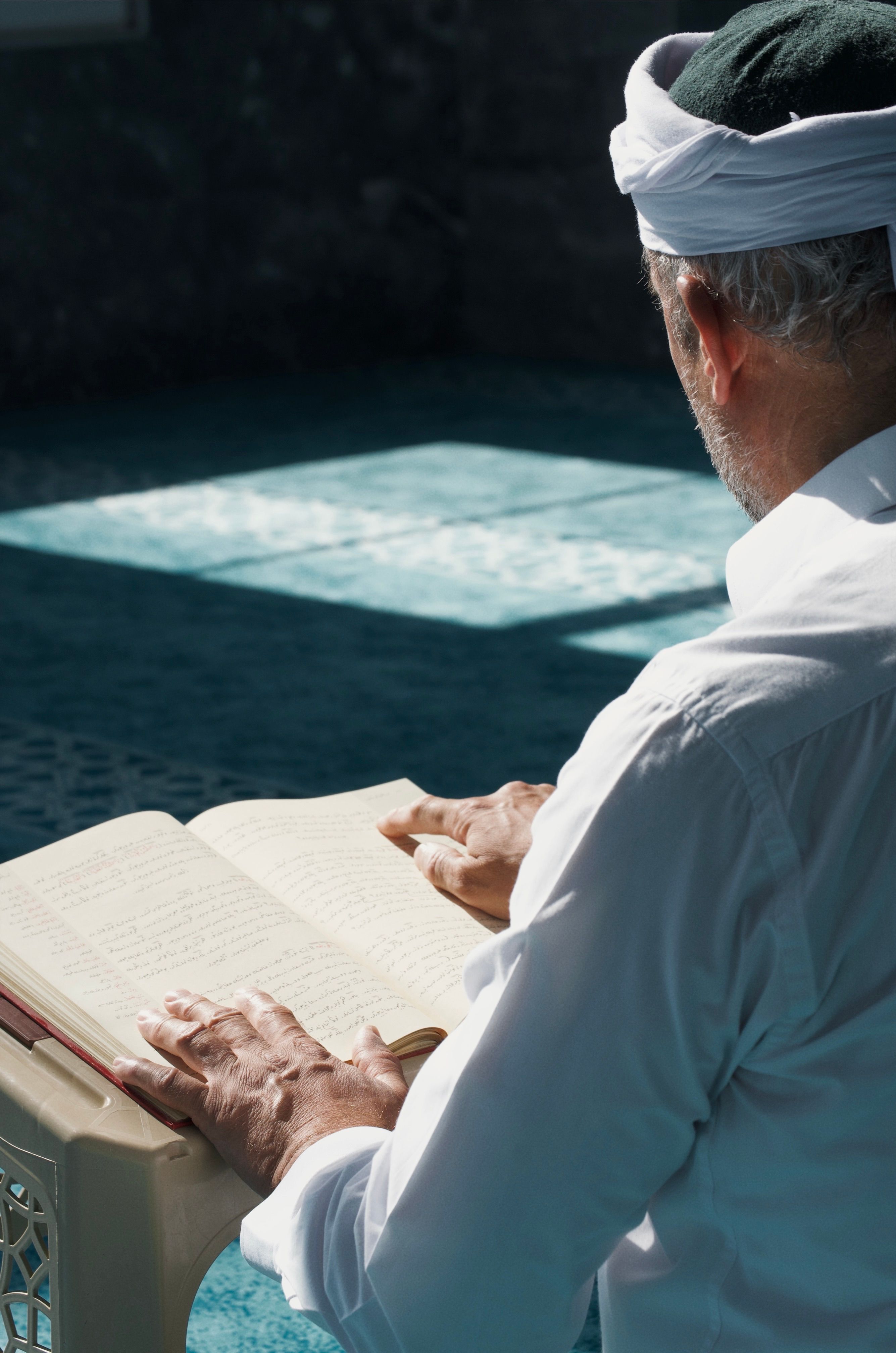Man Reading Holy Book in Sunlit Room · Free Stock Photo
