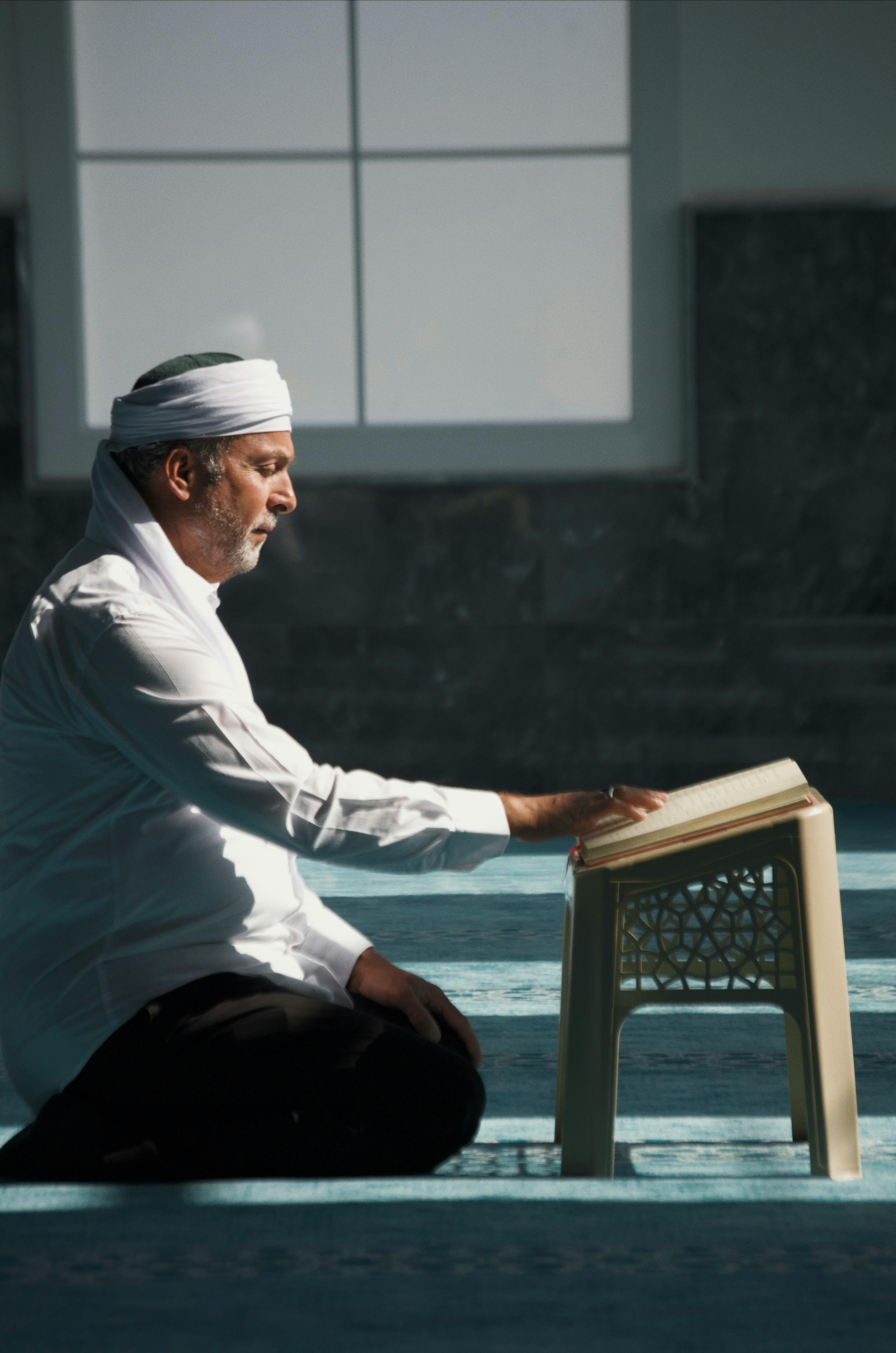 Middle-aged man reading in serene mosque setting · Free Stock Photo