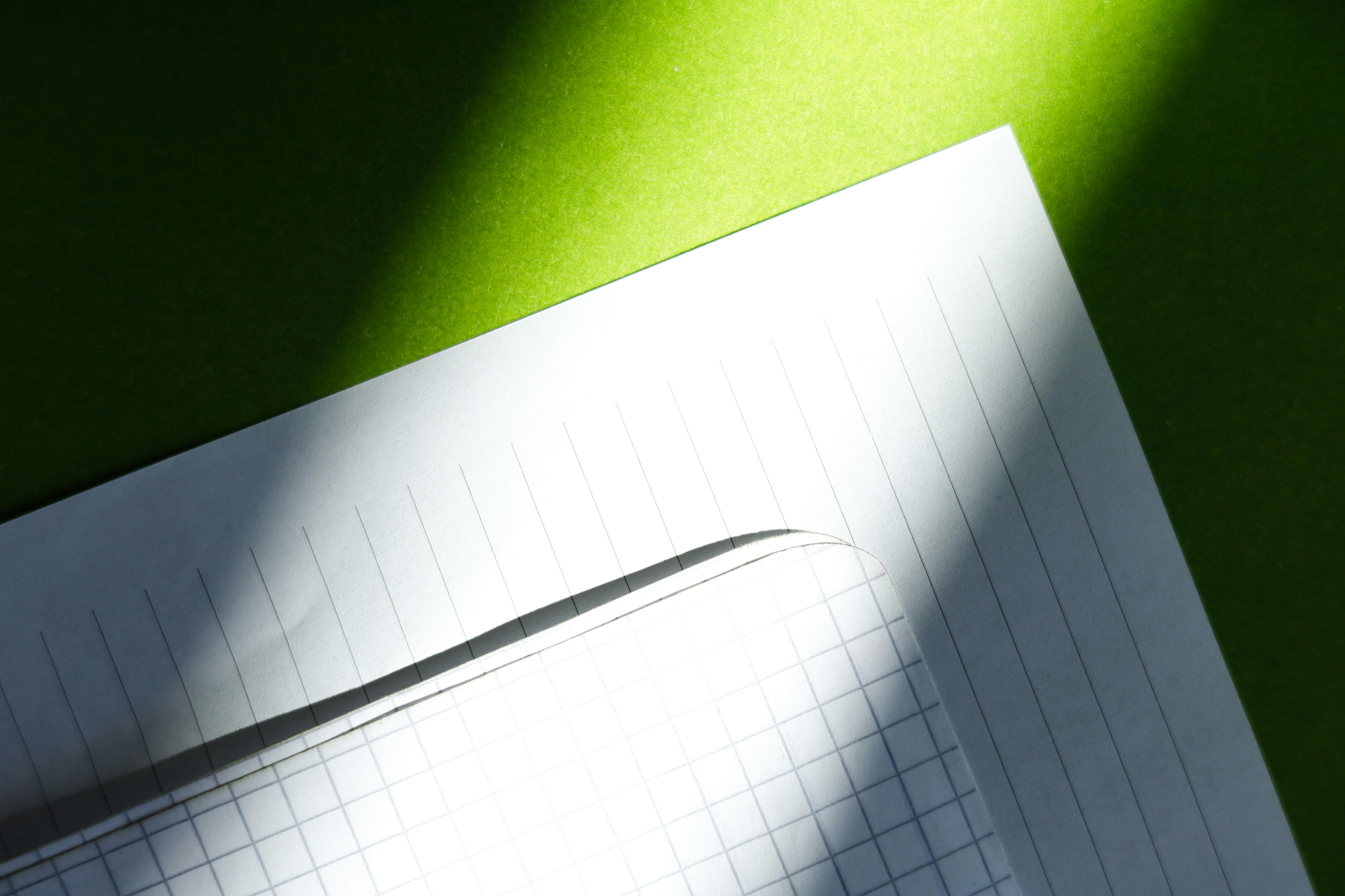 Sunlit Close-Up of Ruled and Graph Paper Sheets · Free Stock Photo