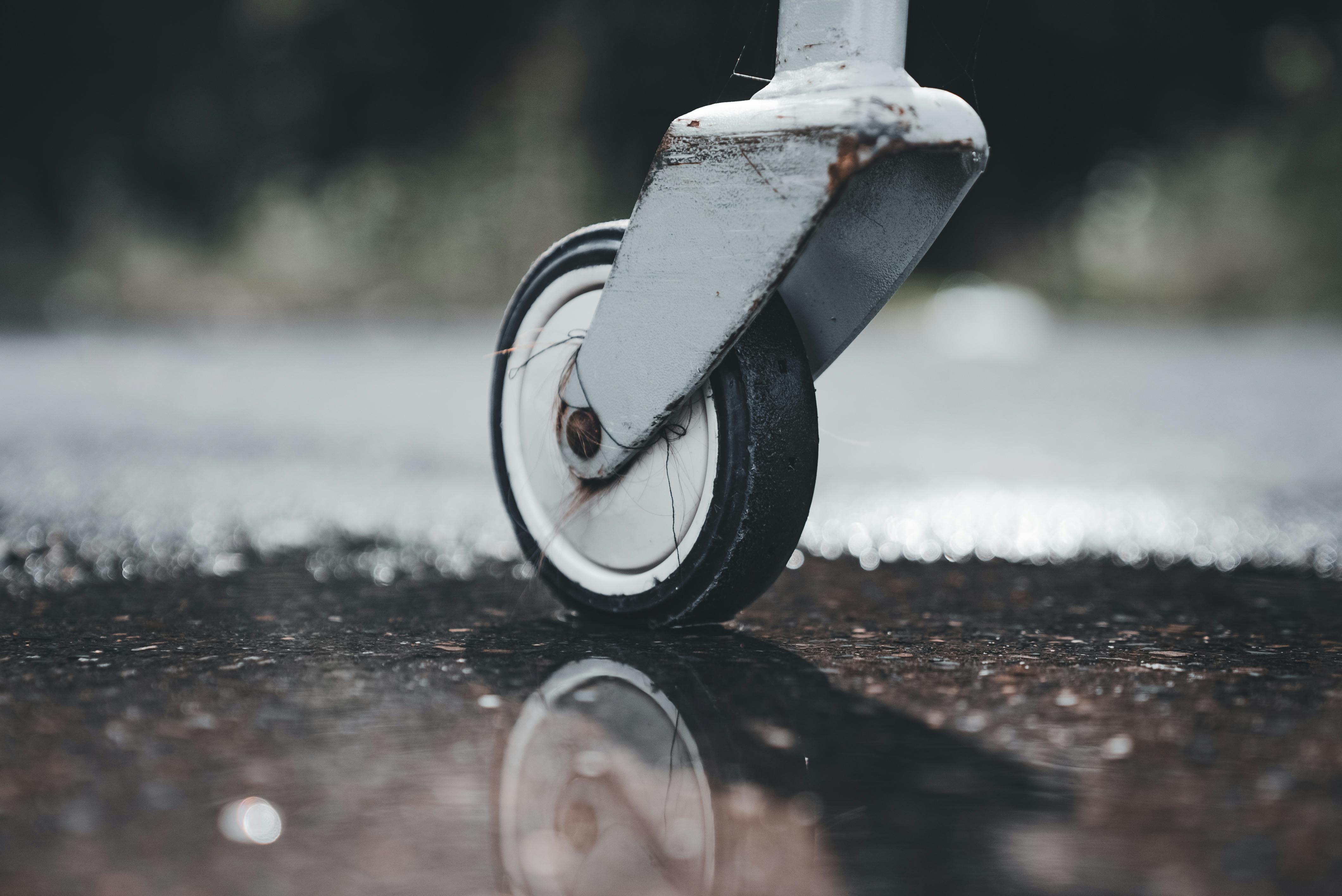Close-up of Wet Castor Wheel in Reflective Puddle · Free Stock Photo