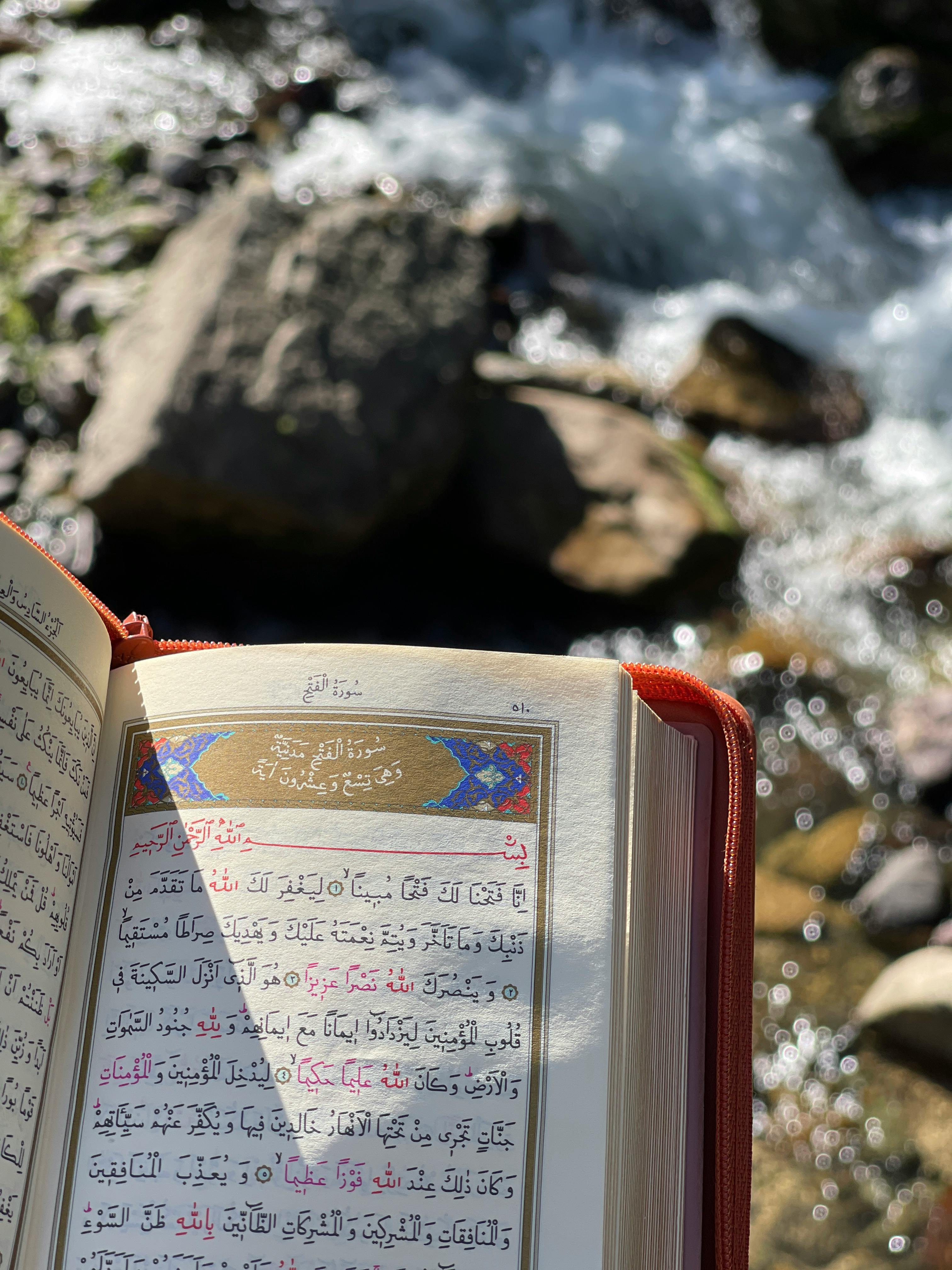 Open Quran by a Stream in Natural Light · Free Stock Photo