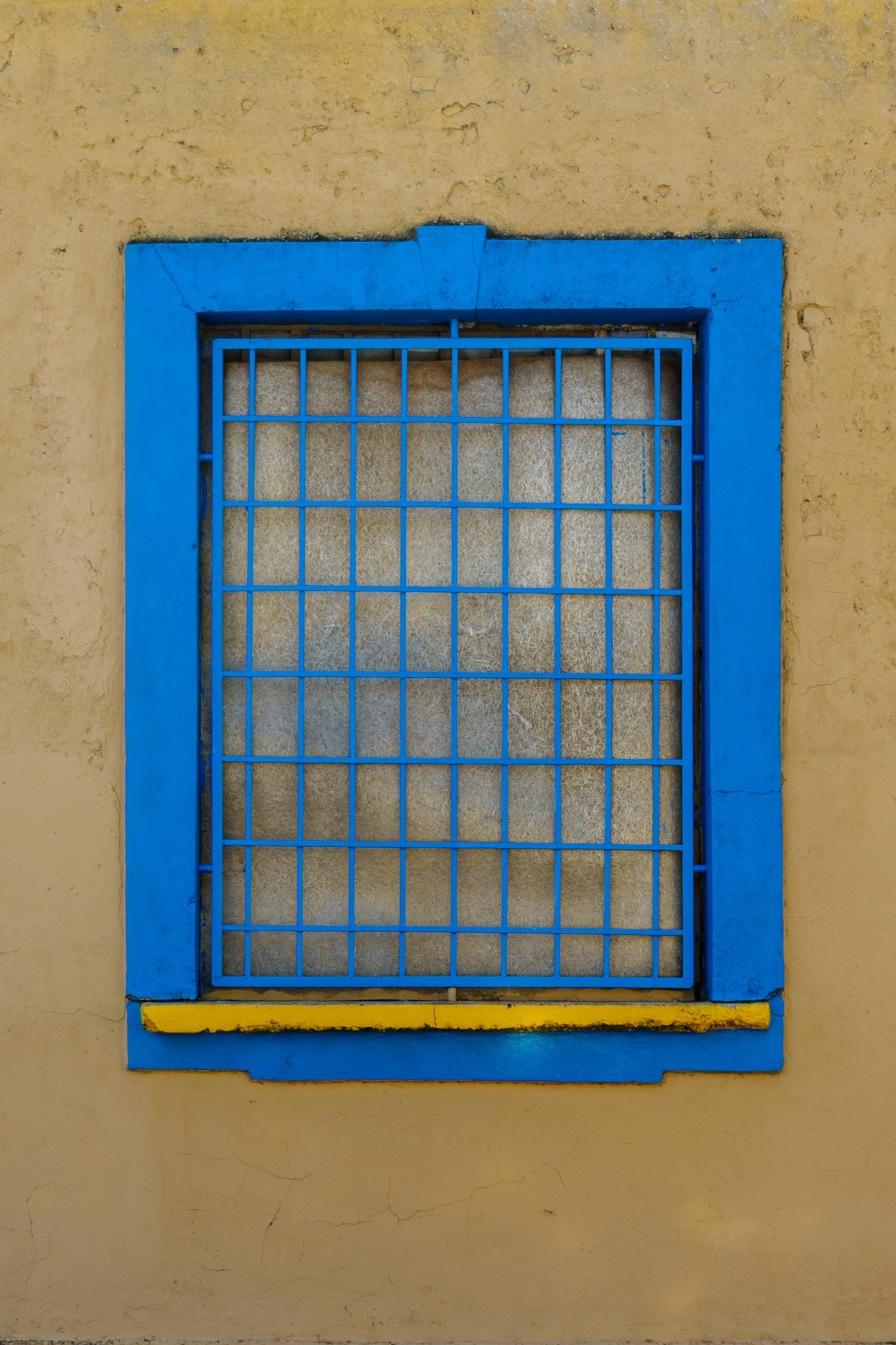 Vibrant Blue Window on Textured Yellow Wall · Free Stock Photo