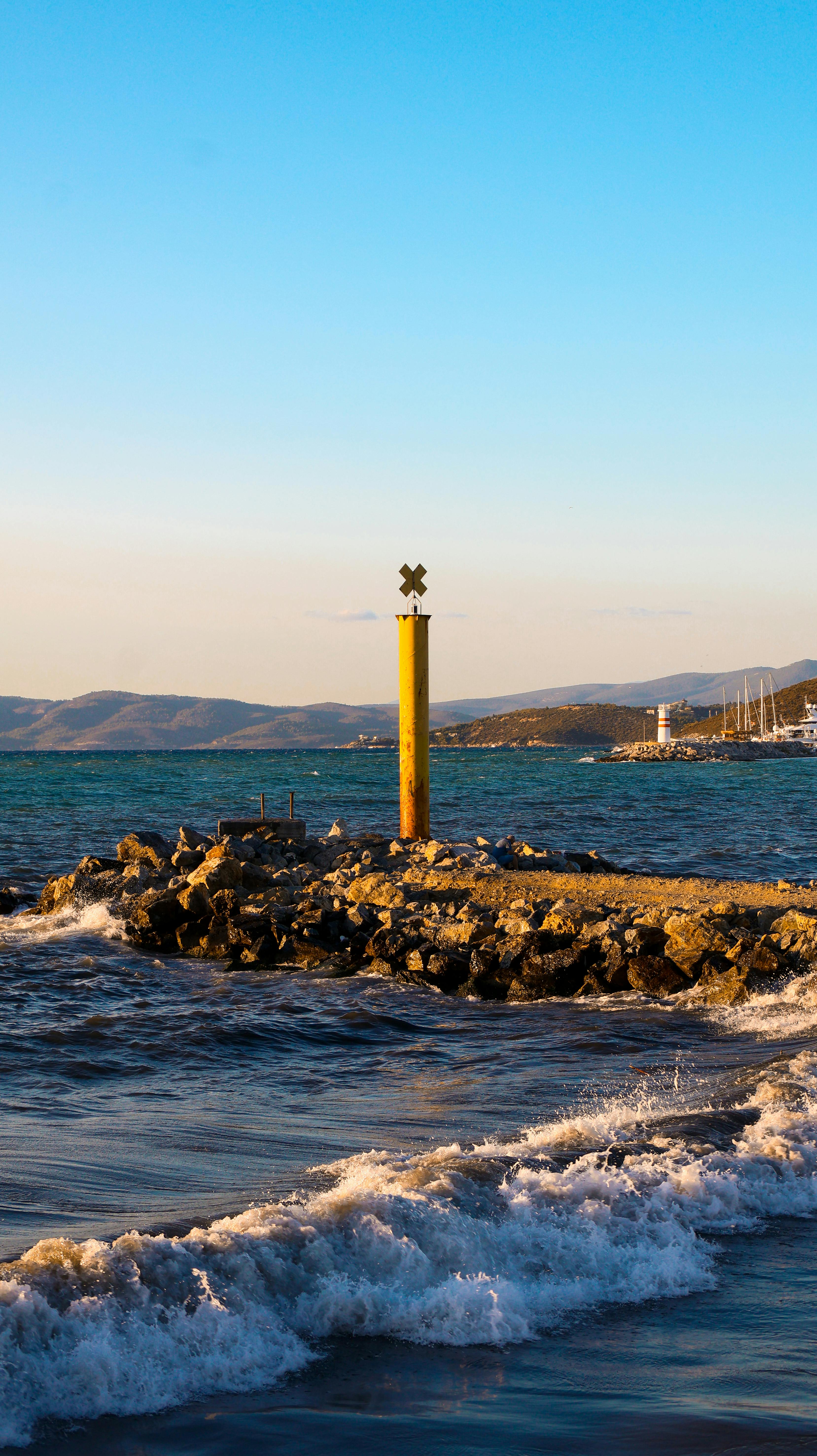 Coastal Rock Pier with Yellow Marker at Sunset · Free Stock Photo