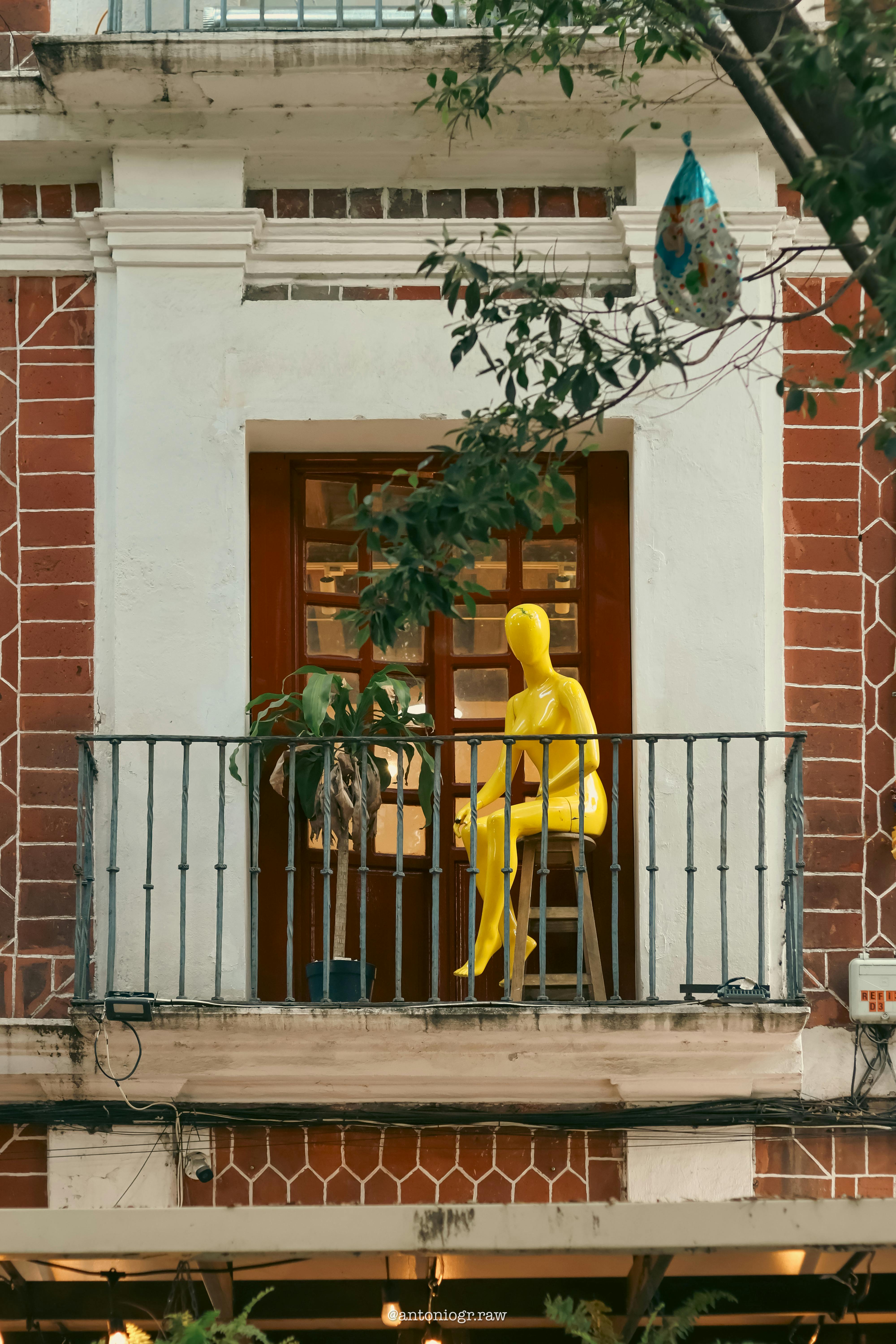 Bright Yellow Mannequin on Urban Balcony · Free Stock Photo