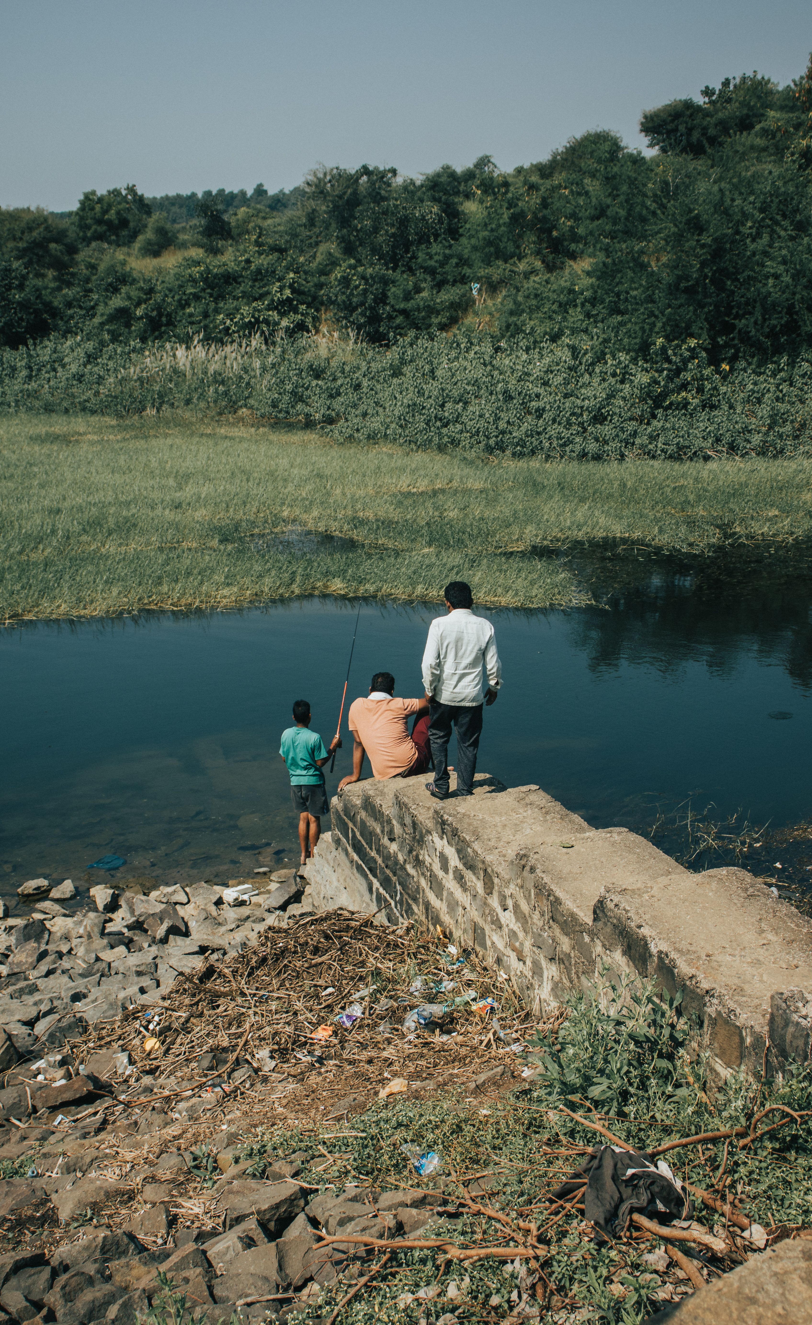 Three Men Fishing by a Riverside in Nature · Free Stock Photo