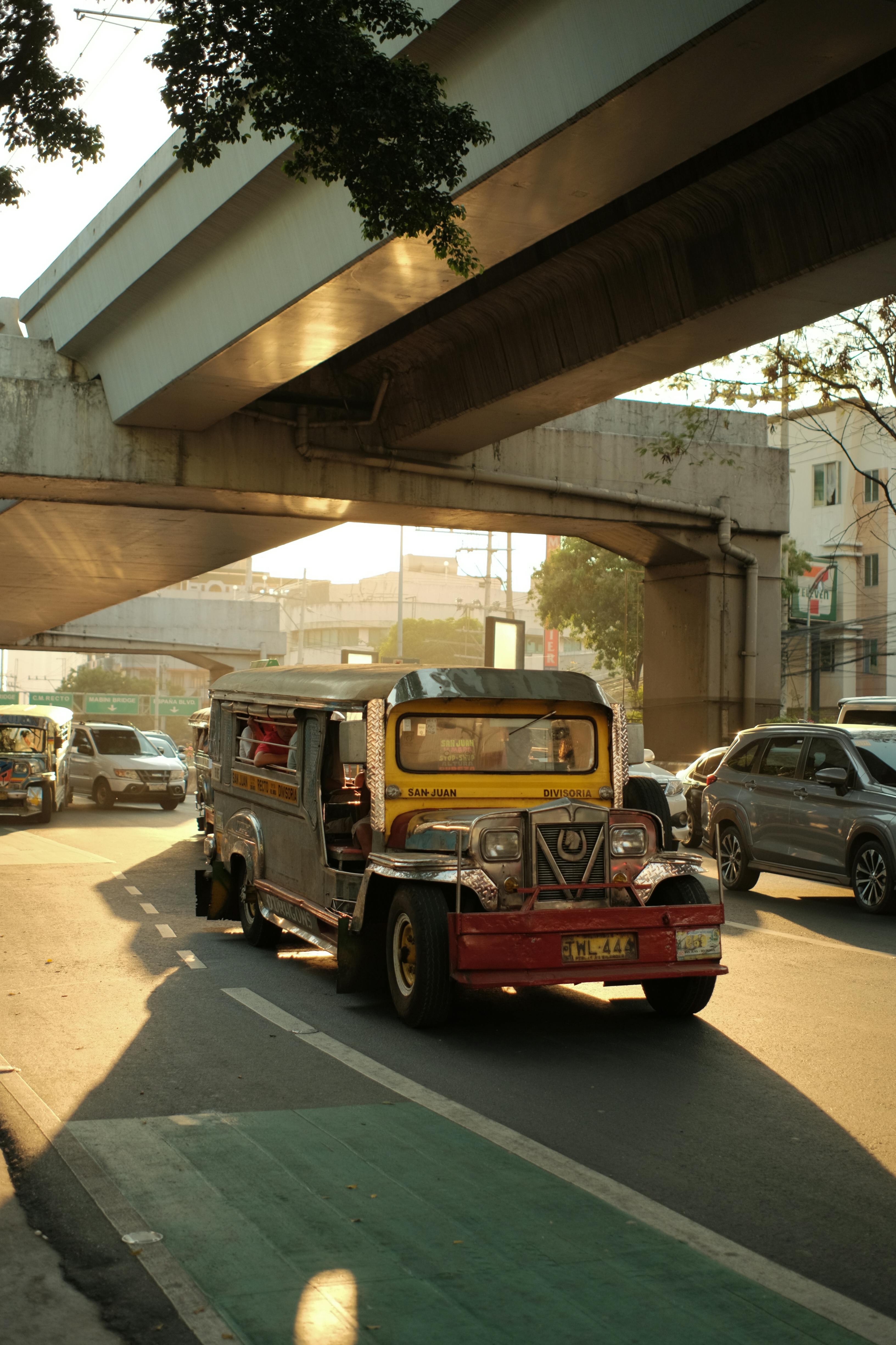 Iconic Jeepney Driving Through Manila Street at Sunset · Free Stock Photo