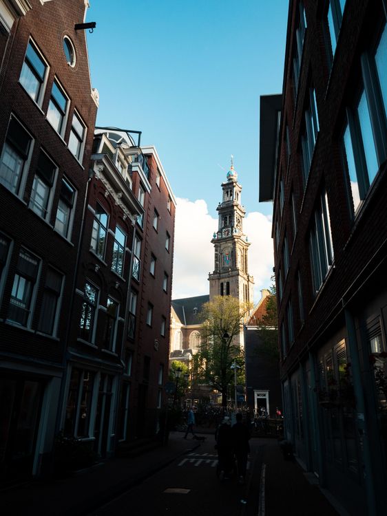 View of the Westerkerk tower framed between traditional Amsterdam buildings