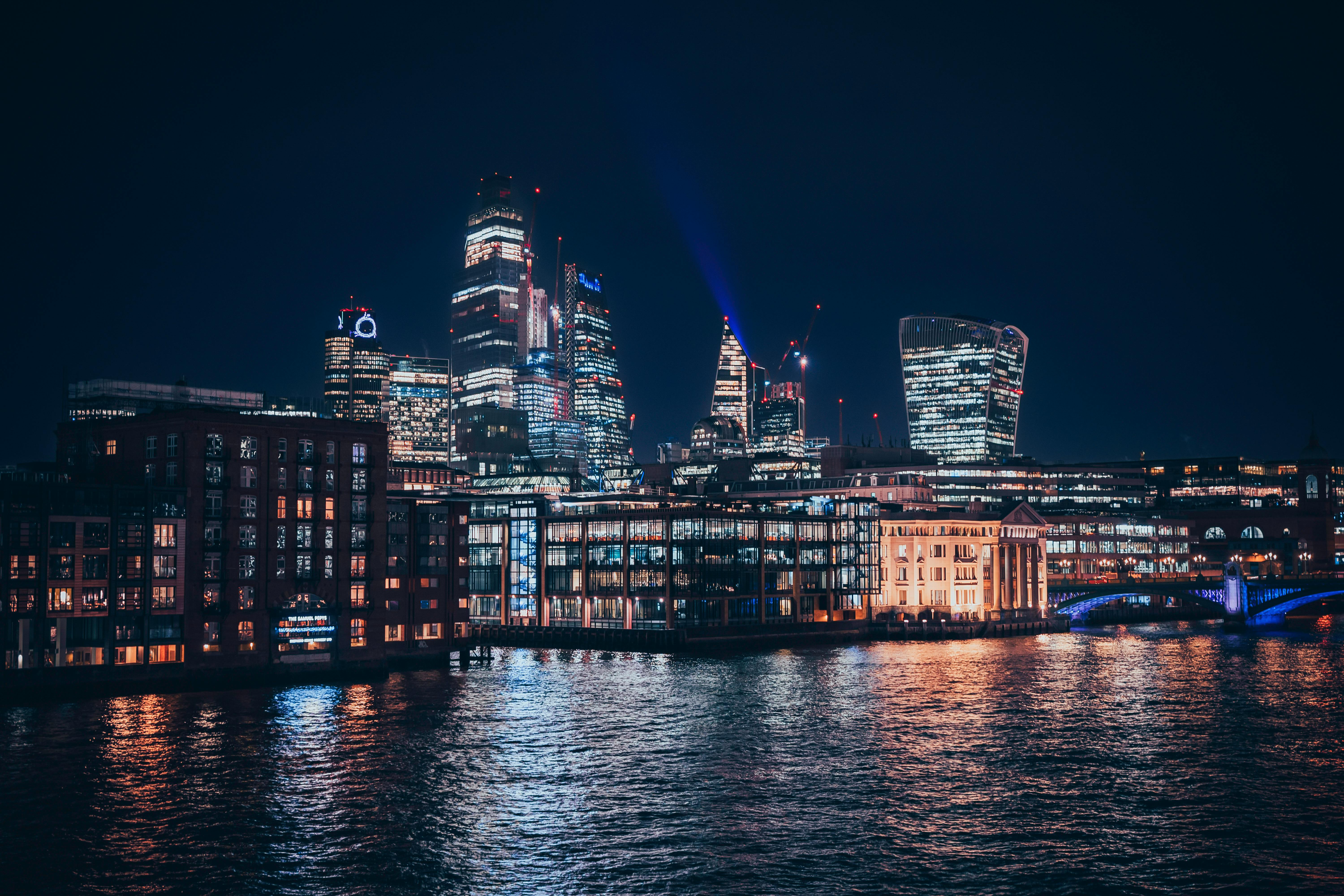 Low Light Photo of Lighted Buildings in Front of Body of Water · Free ...