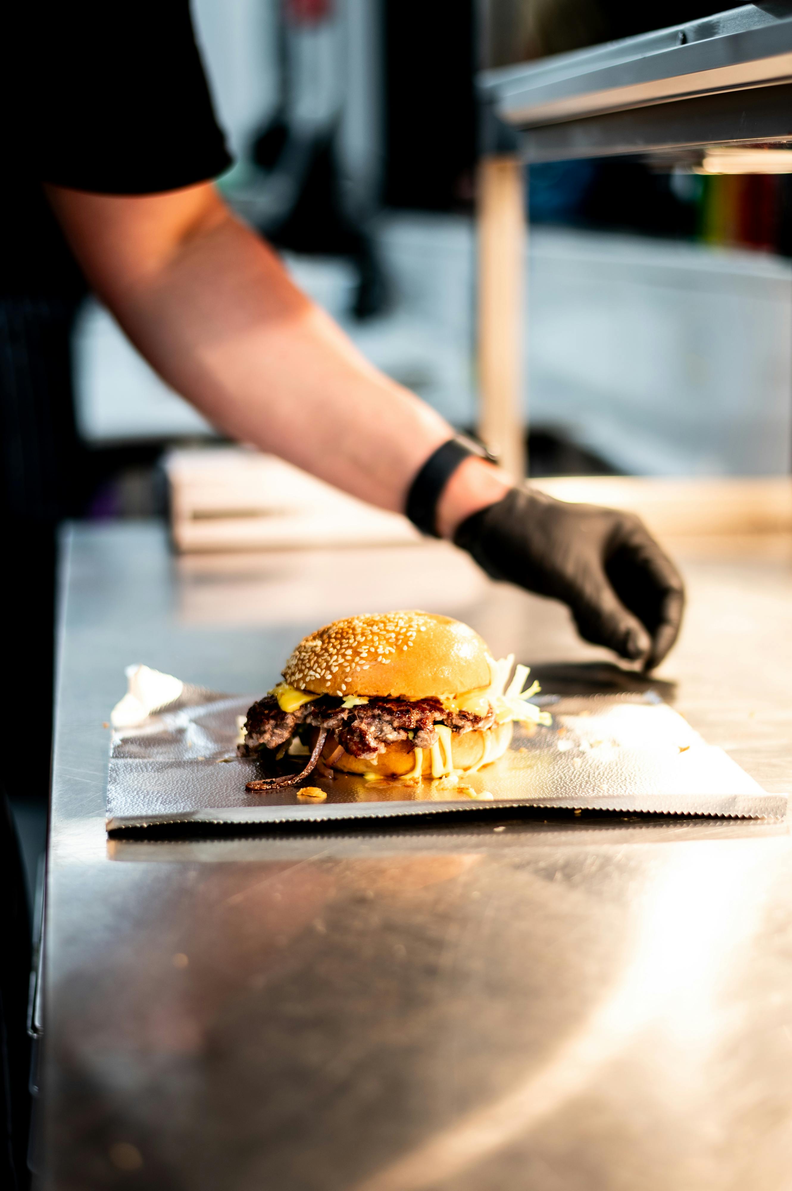 Chef presenting gourmet burger in kitchen · Free Stock Photo