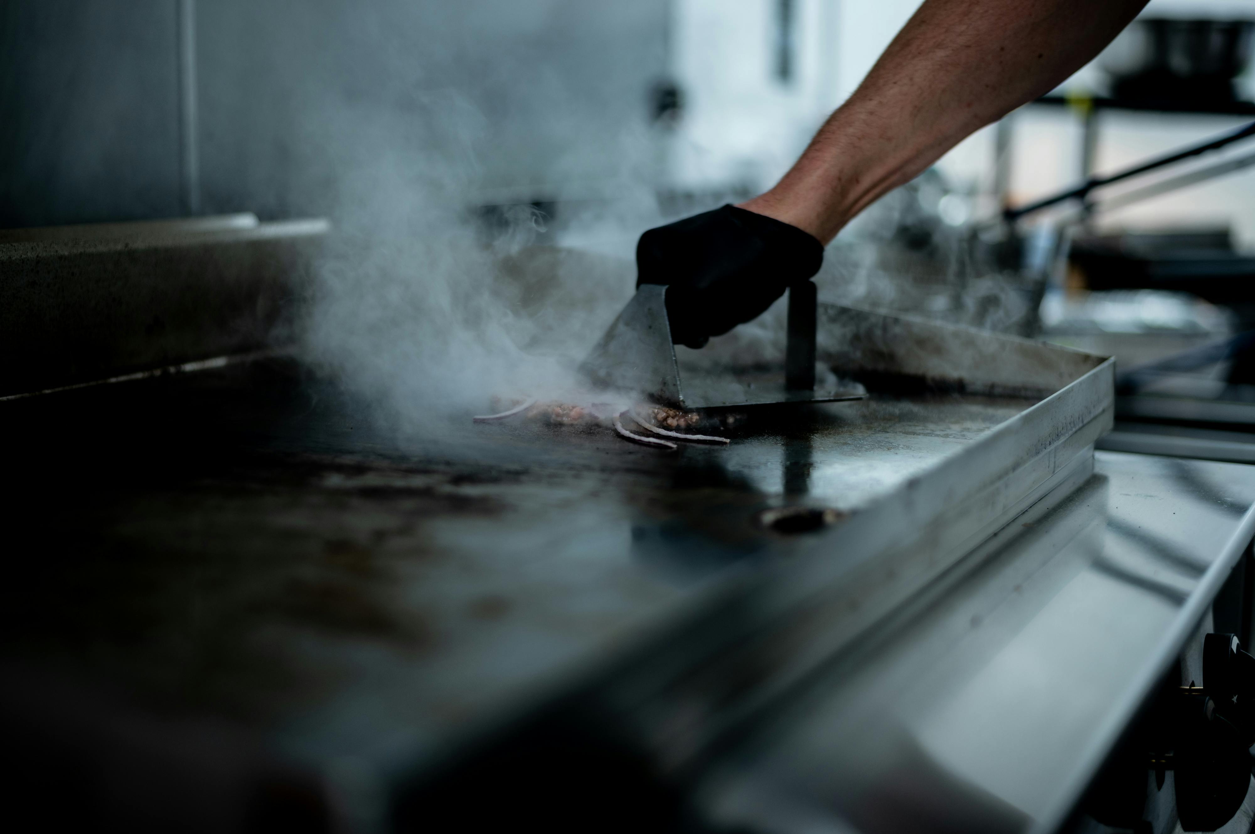 Chef Grilling Meat on Smoky Industrial Griddle · Free Stock Photo