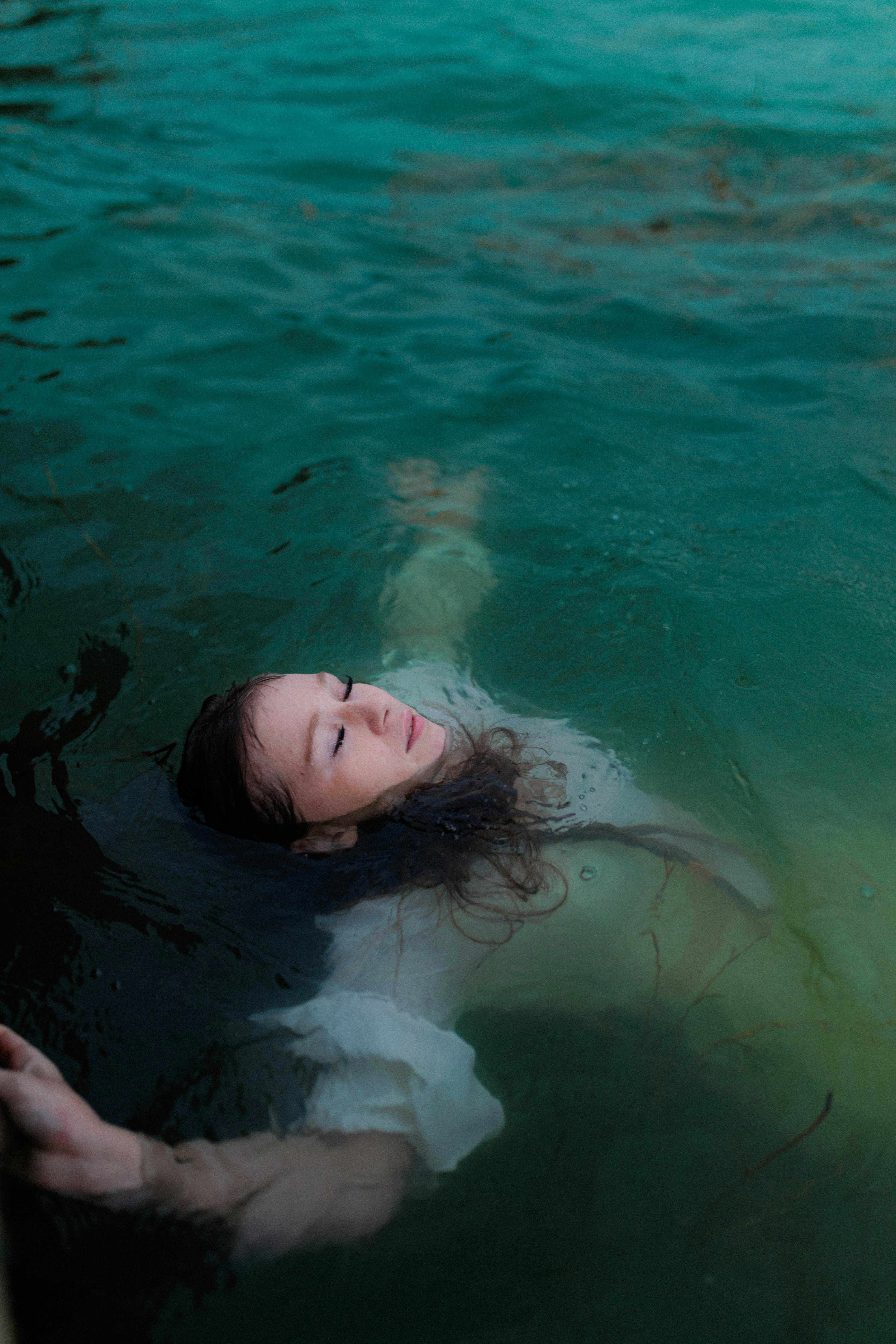 Woman Floating on Water with Water Lilies · Free Stock Photo
