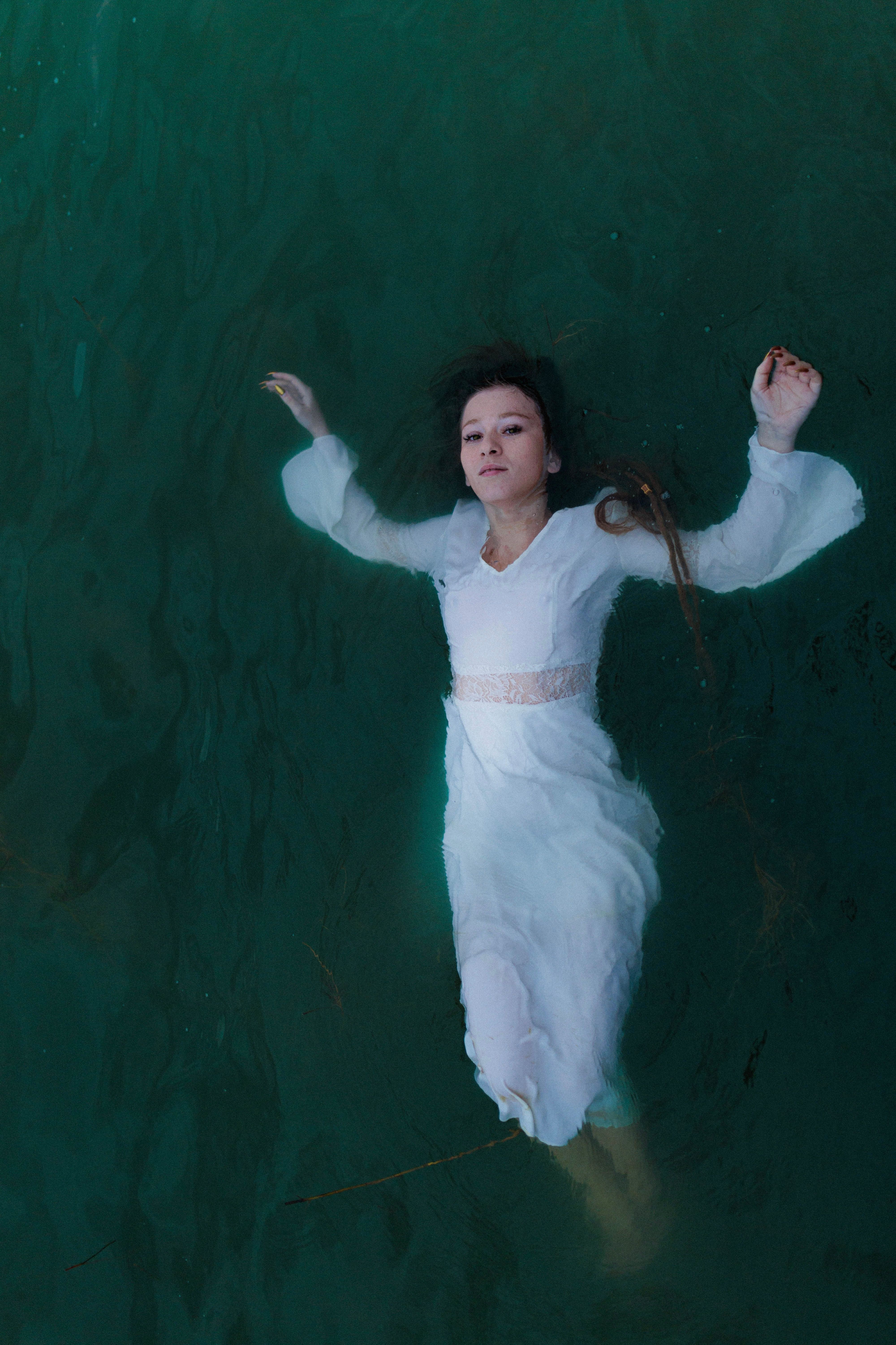 Serene Woman Floating on Water in White Dress · Free Stock Photo