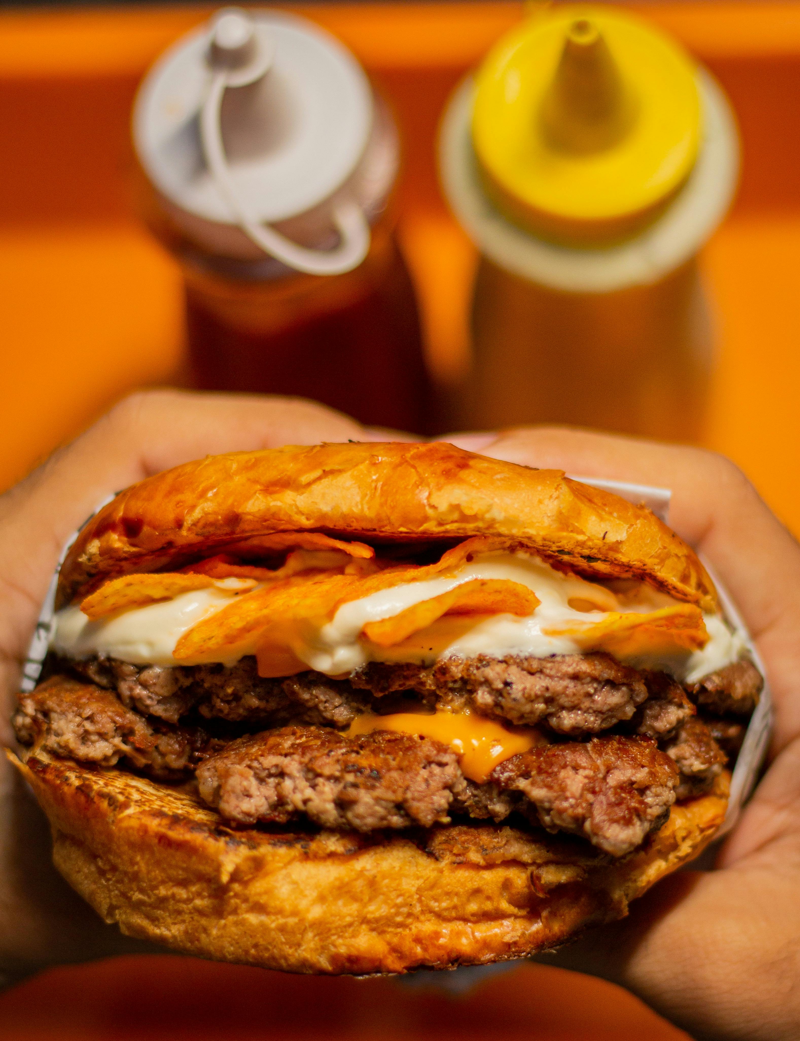 Close-up of Juicy Cheeseburger with Condiments · Free Stock Photo