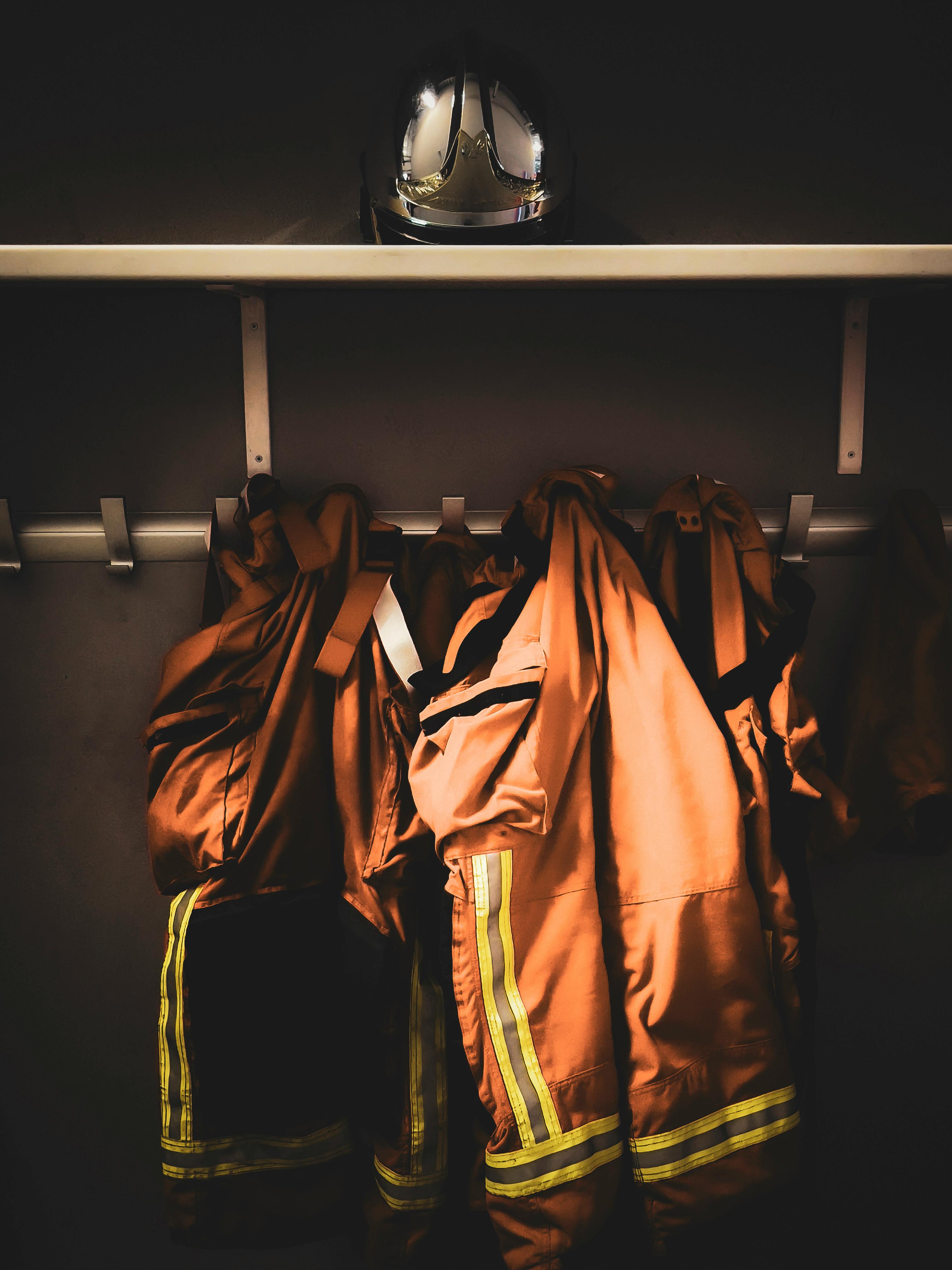 Firefighter Gear Hanging in Dark Locker Room · Free Stock Photo