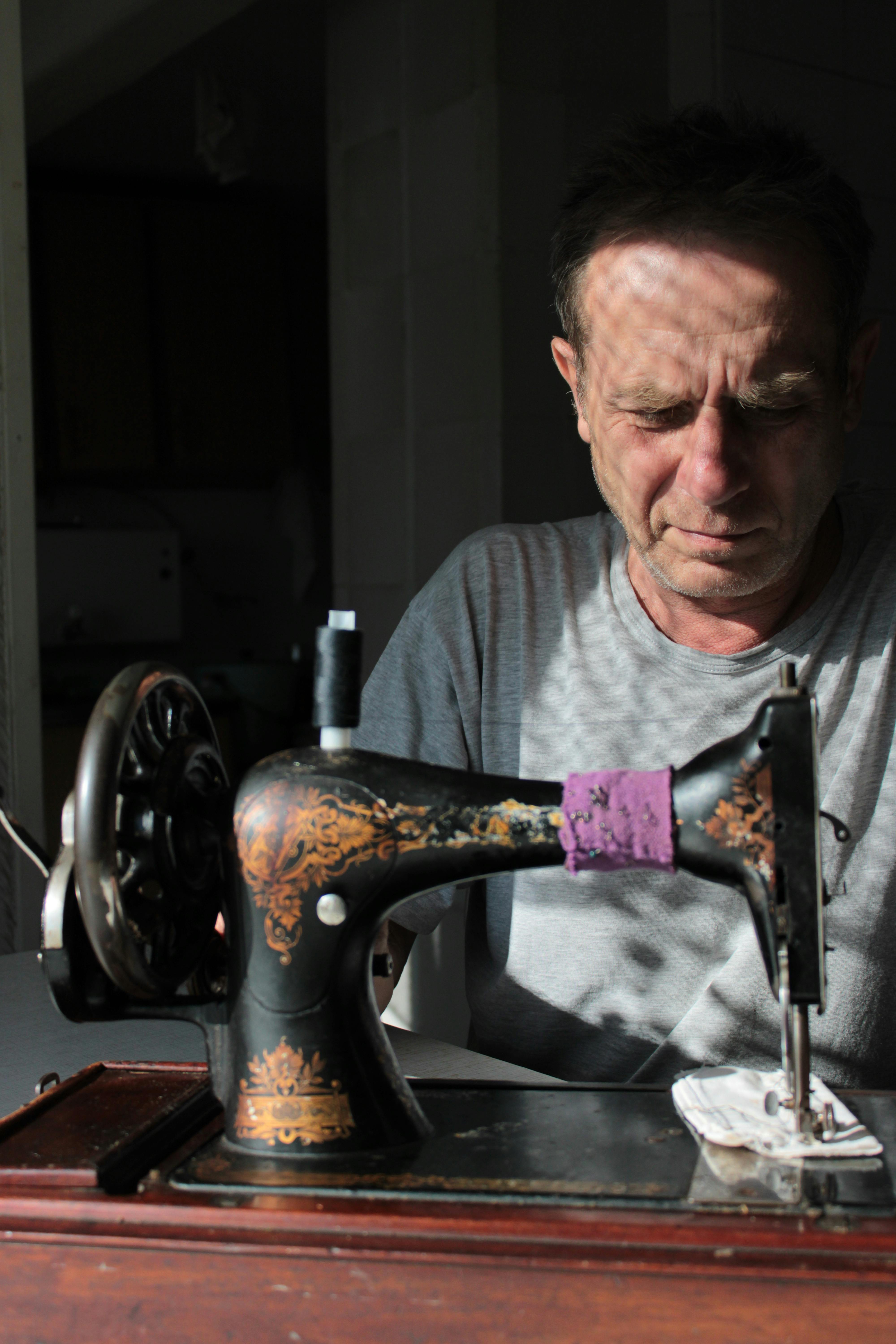 Elderly Man Sewing with Vintage Sewing Machine · Free Stock Photo