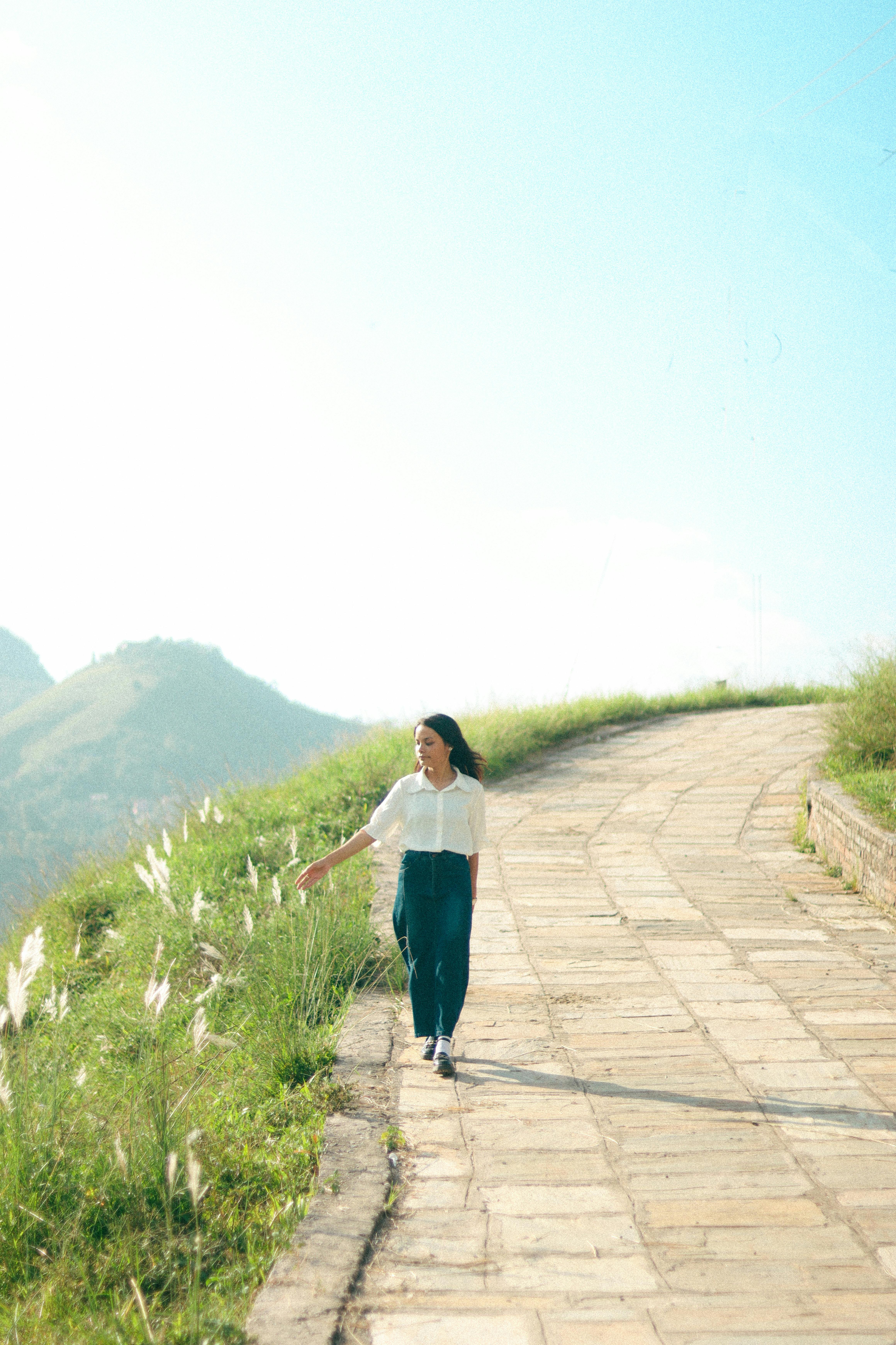 Woman Walking on Hilltop Path in Sunshine · Free Stock Photo