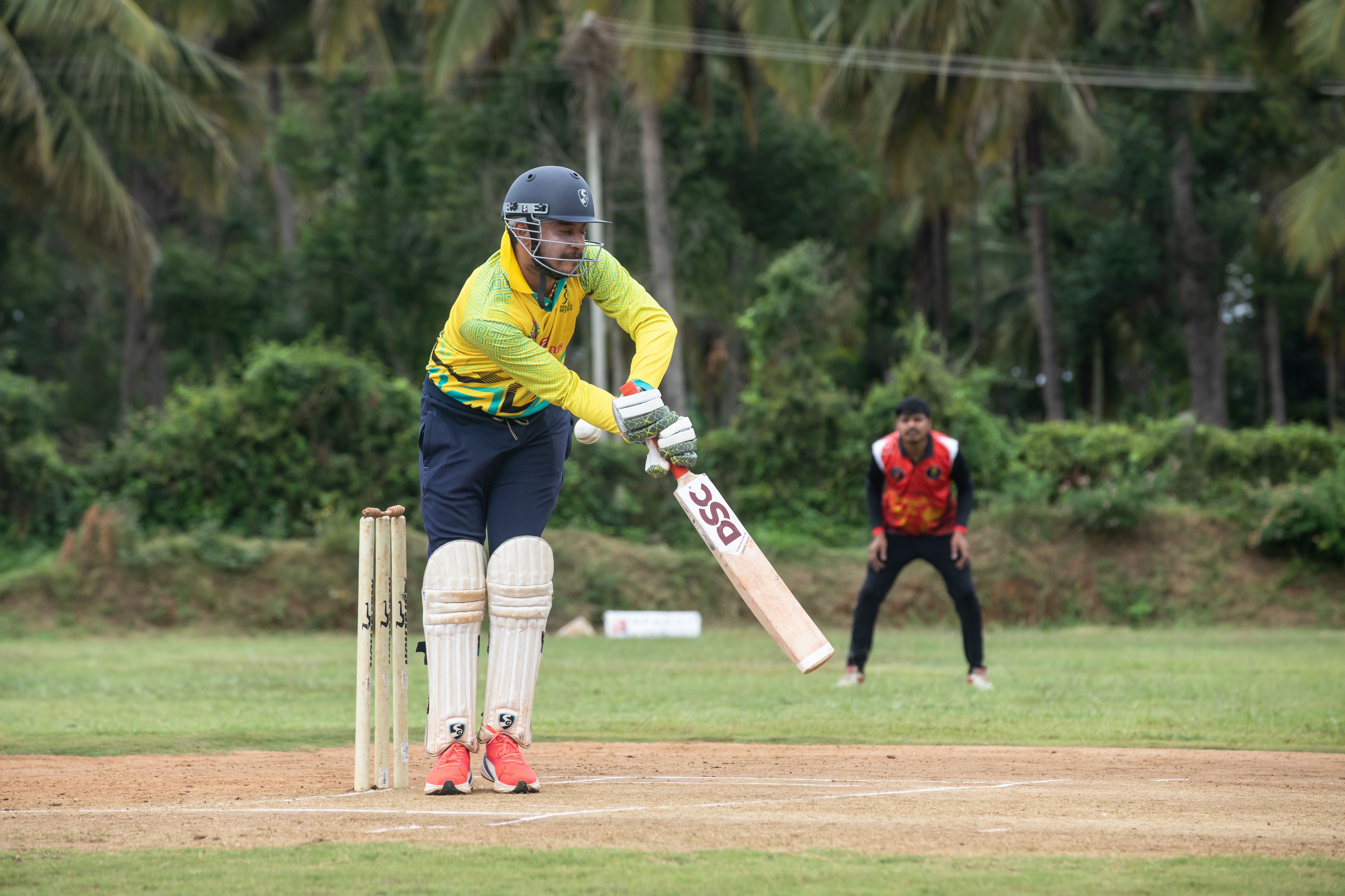Cricket Player Striking Ball on Field · Free Stock Photo
